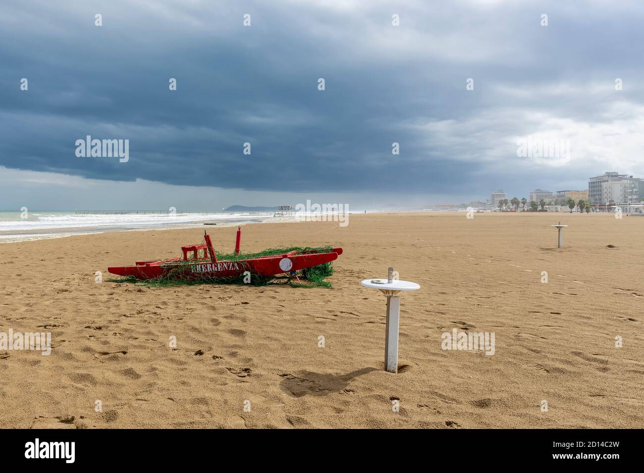 A typical red wooden rescue boat on the beach of Rimini, Italy, during ...