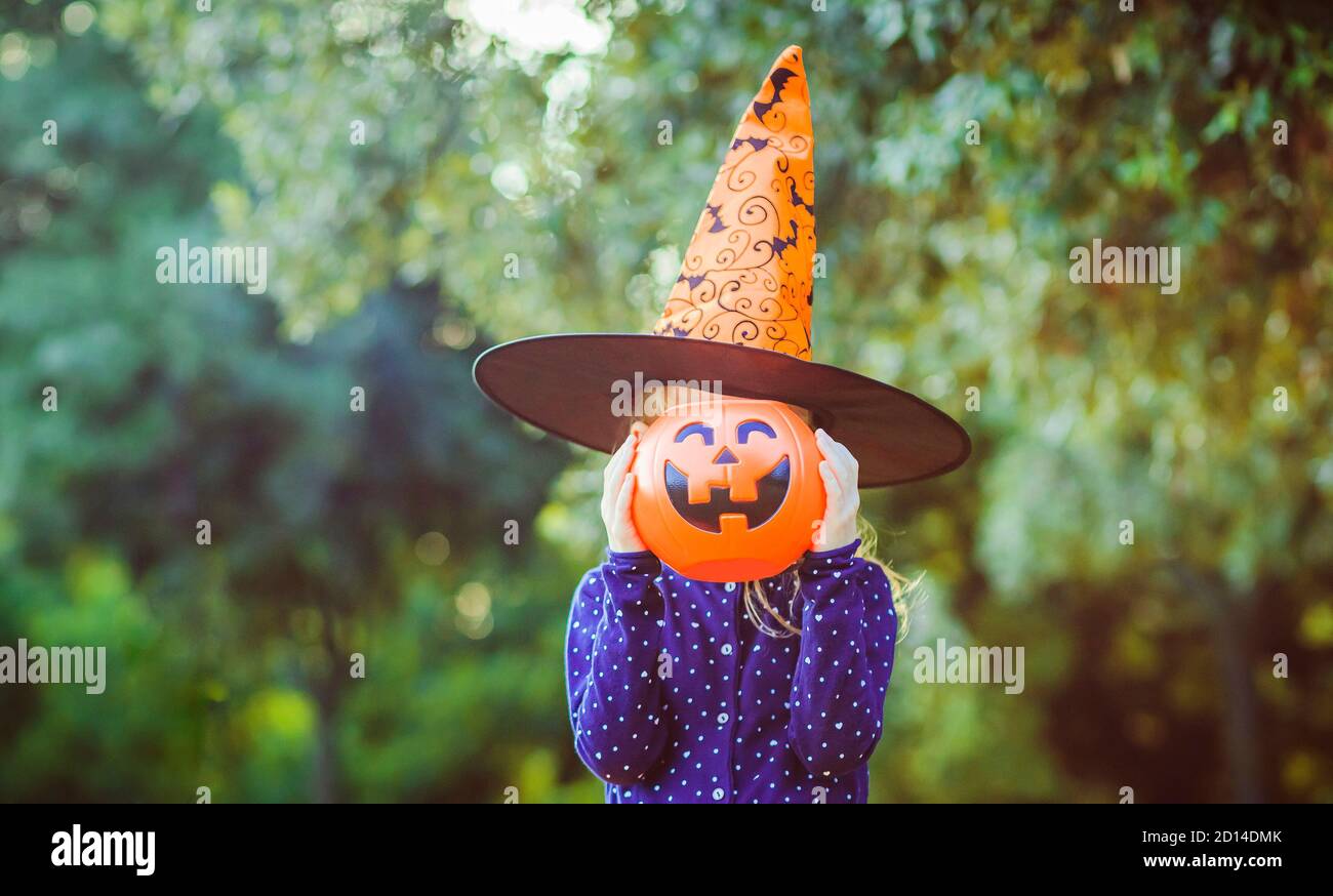 Halloween. Little girl with jack o' lantern in witch hat with pumpkin ...