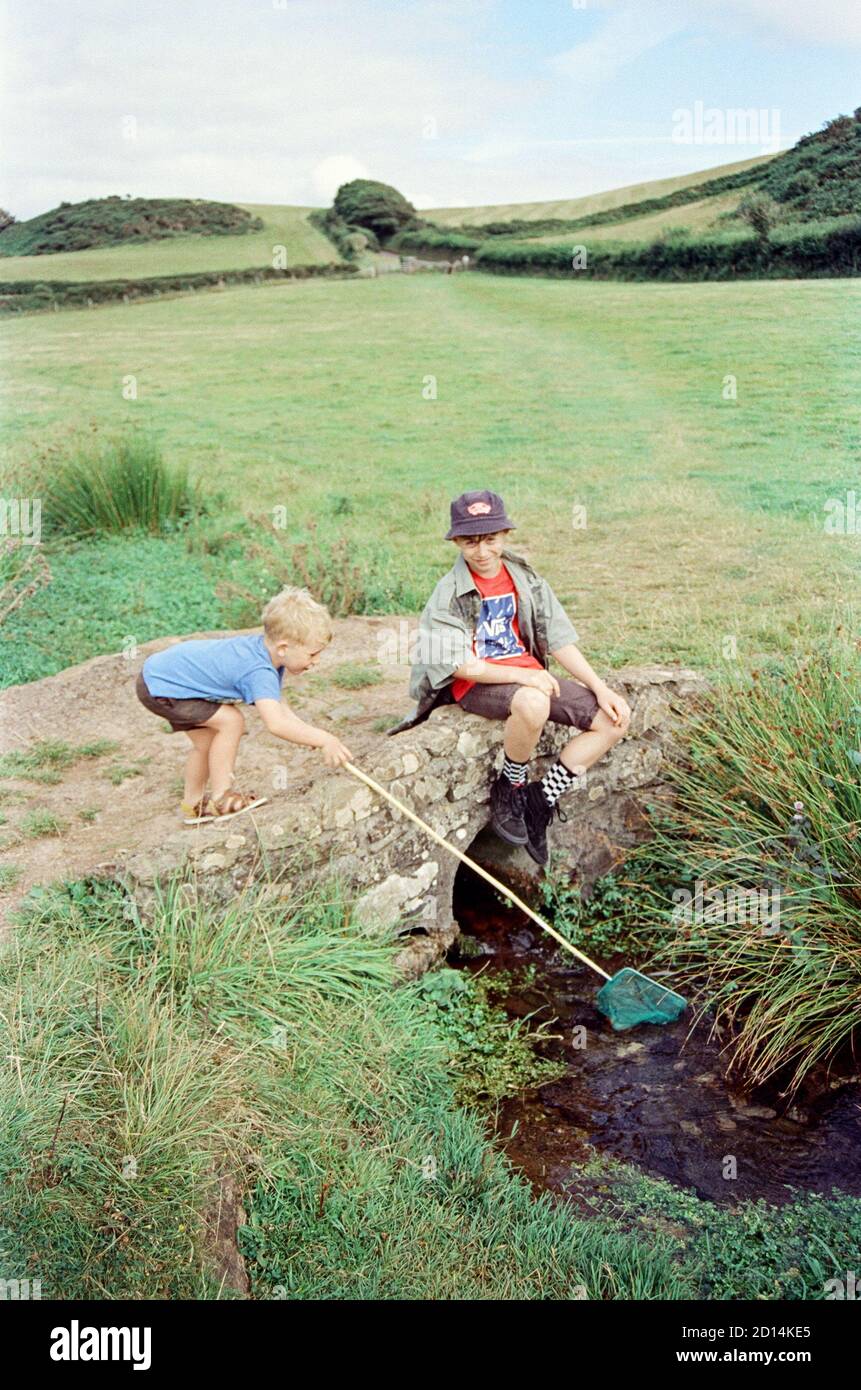 Two boys playing in a small stream, Hope Cove, Devon, England, united ...