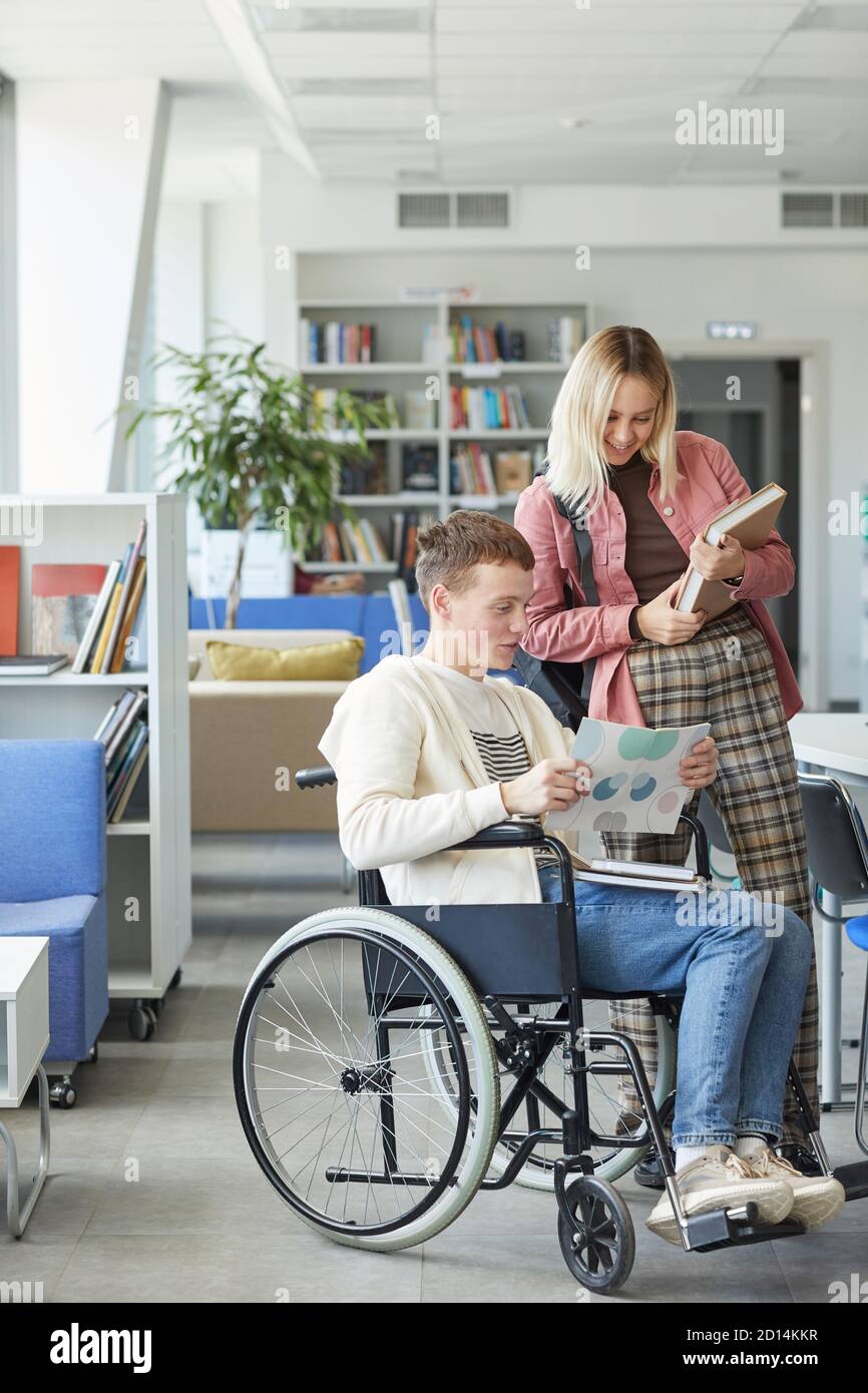 Vertical full length portrait of cheerful disabled student talking to ...