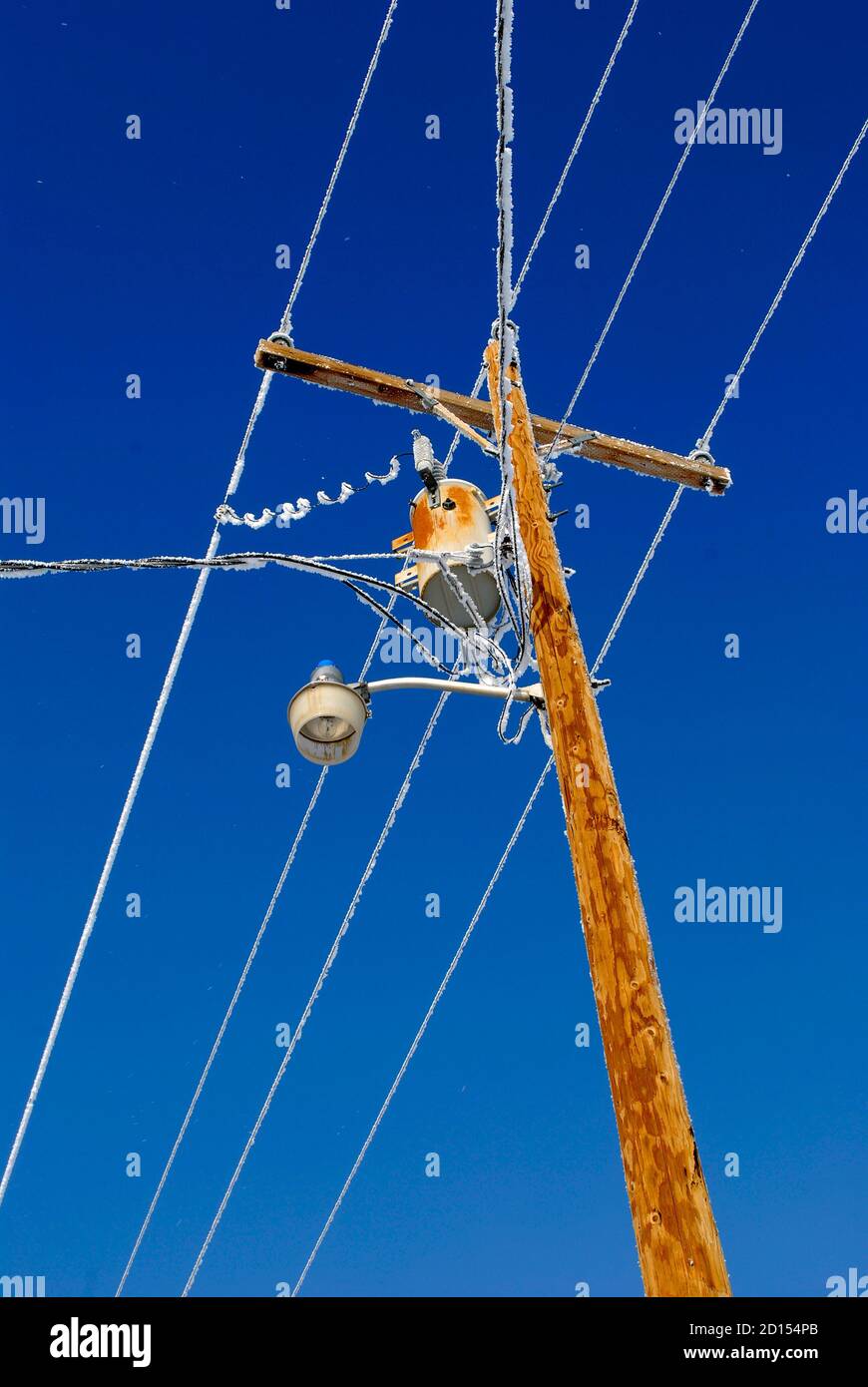 Frozen power lines frost against blue sky with ice crystals in the air ...