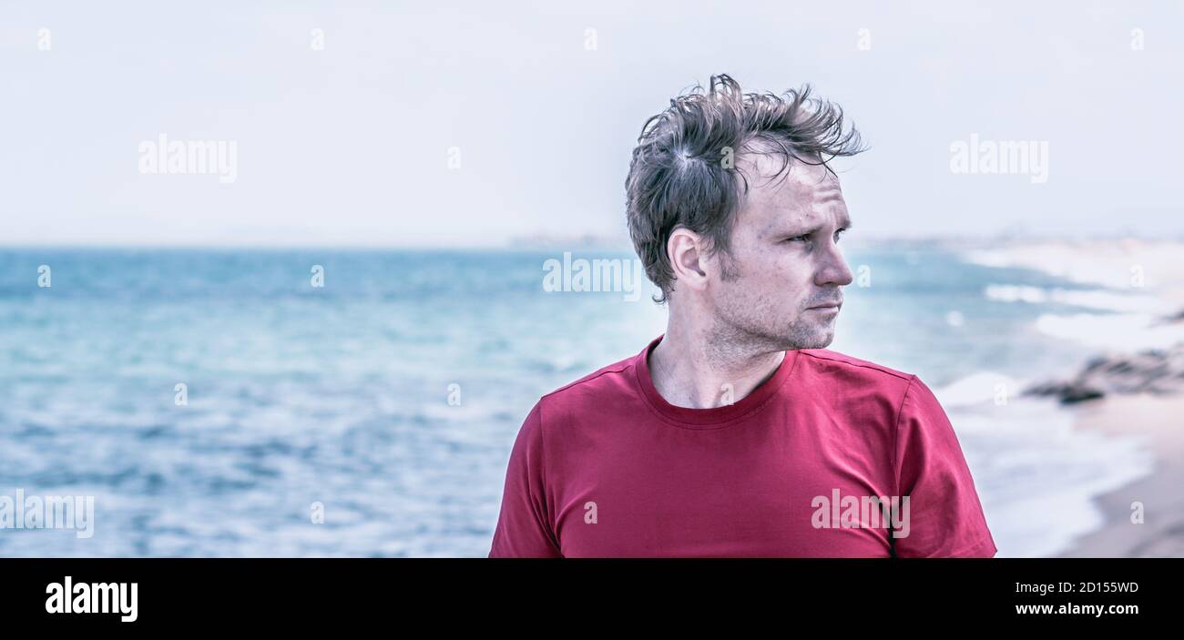 Serious handsome fair hair fluttering wind man red shirt, stubble face ...