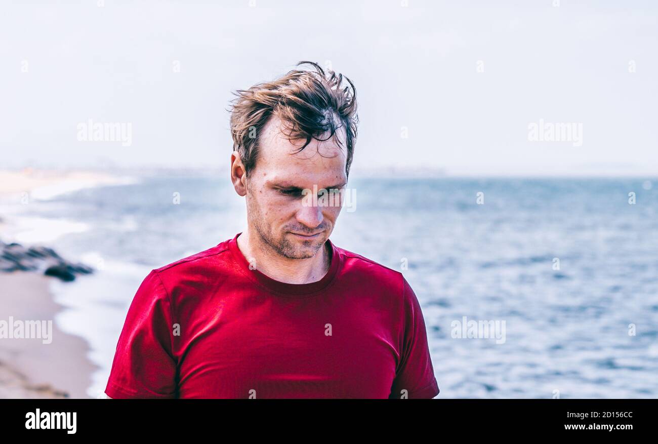 Serious handsome fair hair fluttering wind man red shirt, stubble face ...