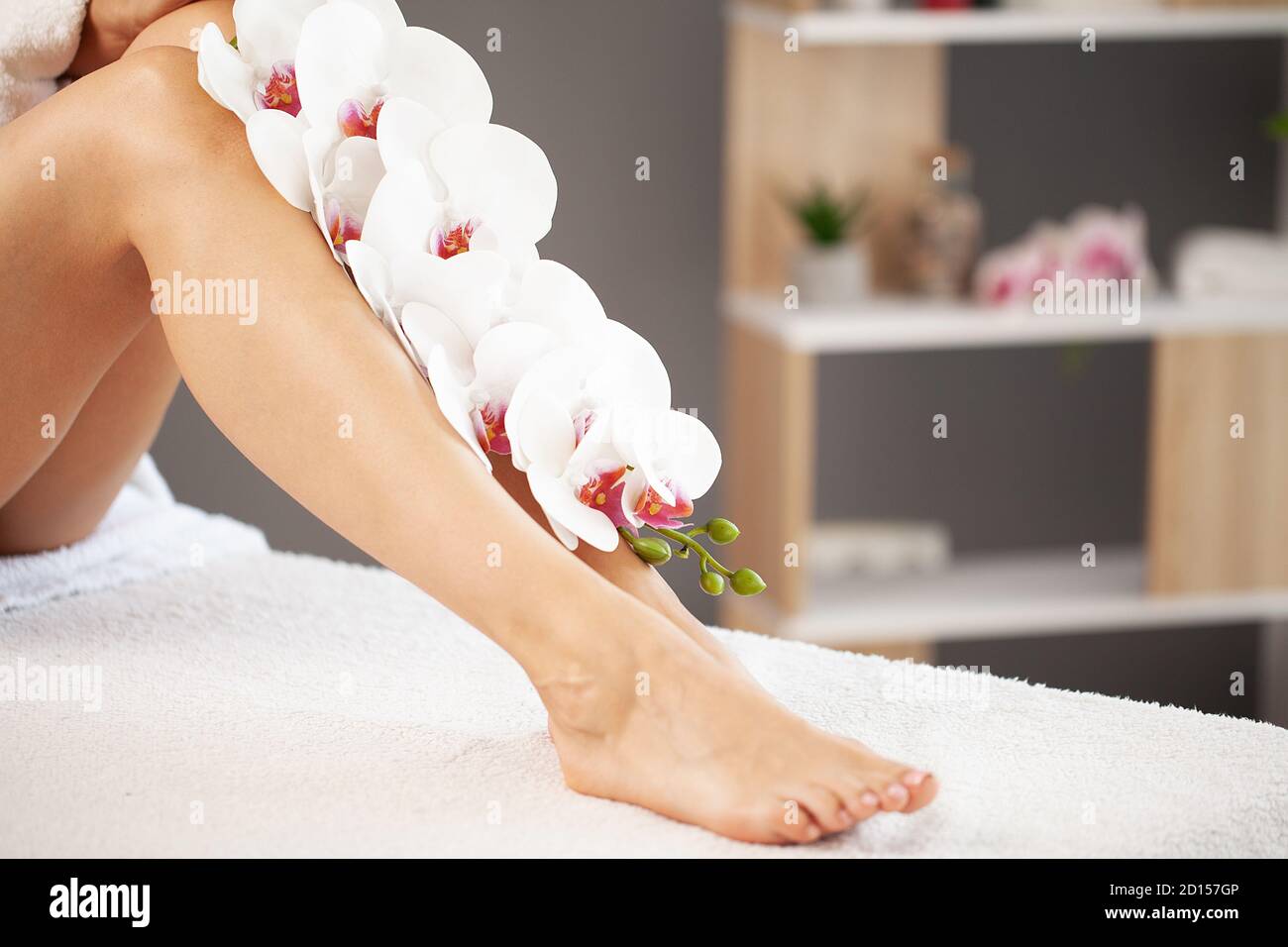 Long legs of a woman with a fresh manicure and orchid flowers Stock ...