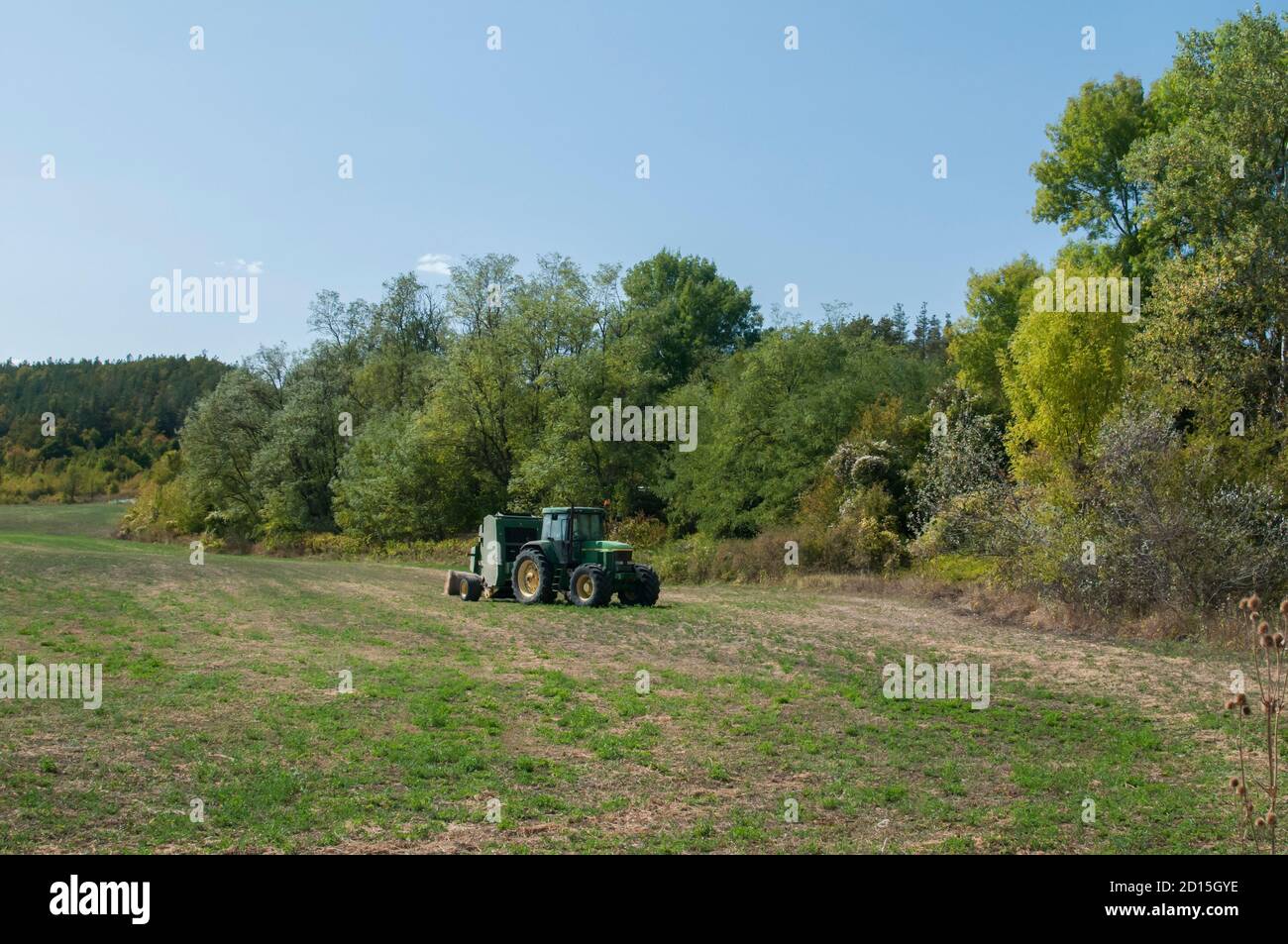 Tractor collecting and baling the cut hay in late summer Stock Photo ...