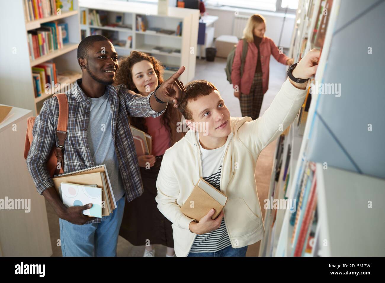 High angle view at multi-ethnic group of students taking books off ...