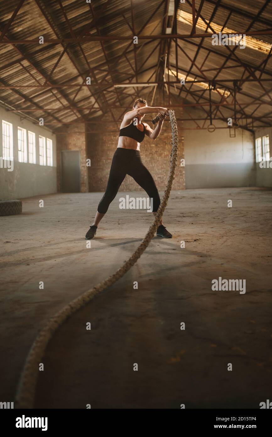 Strong woman using training ropes for exercise. Female working out with ...