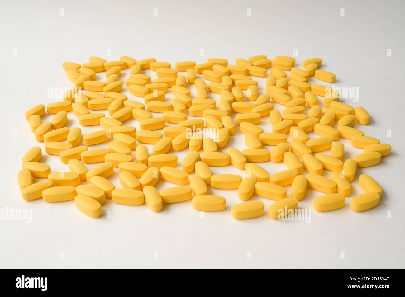 pharmacy concept of handful of yellow tablets lying on a white surface ...