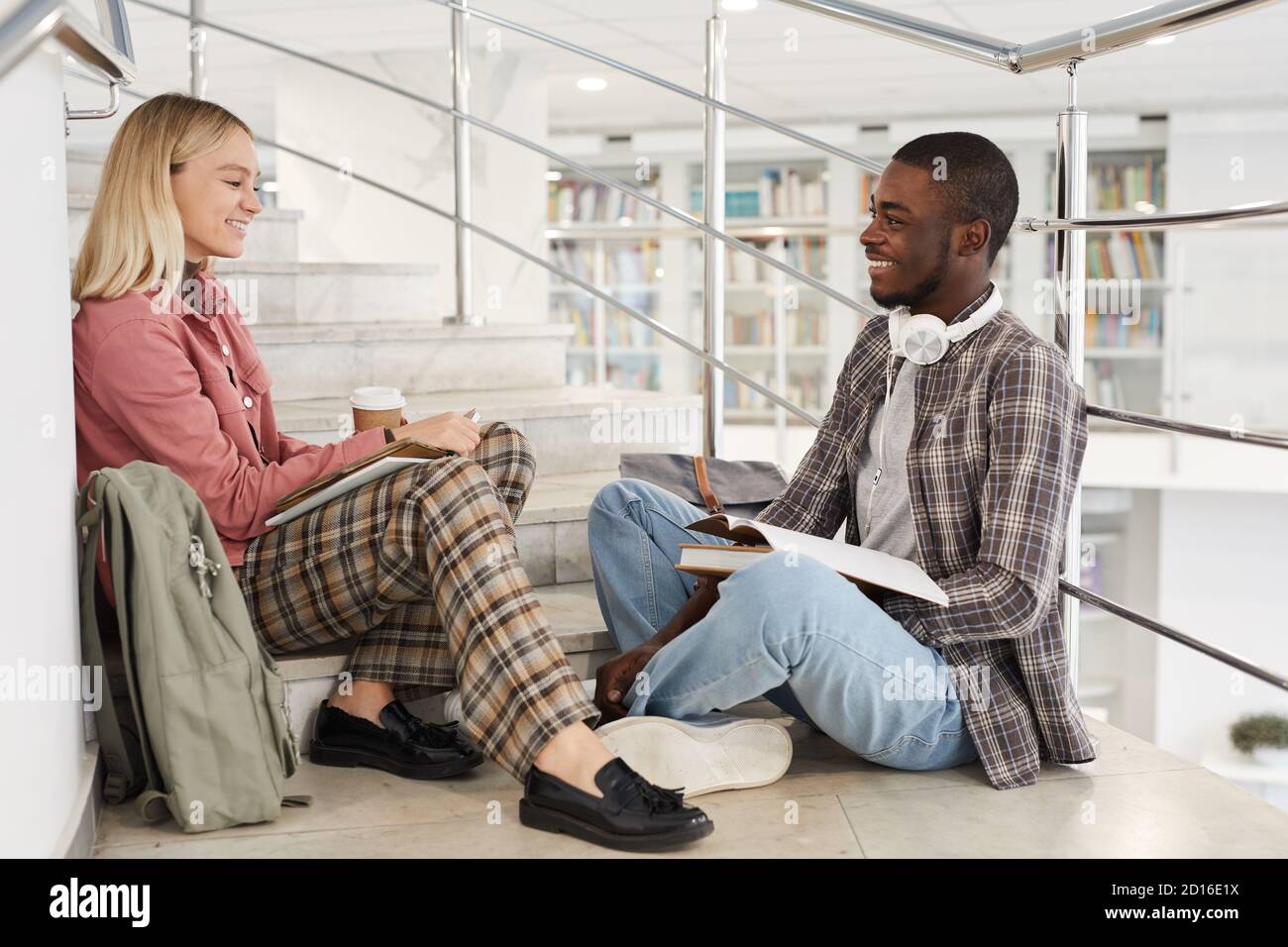 Full length side view portrait of two students chatting while sitting ...