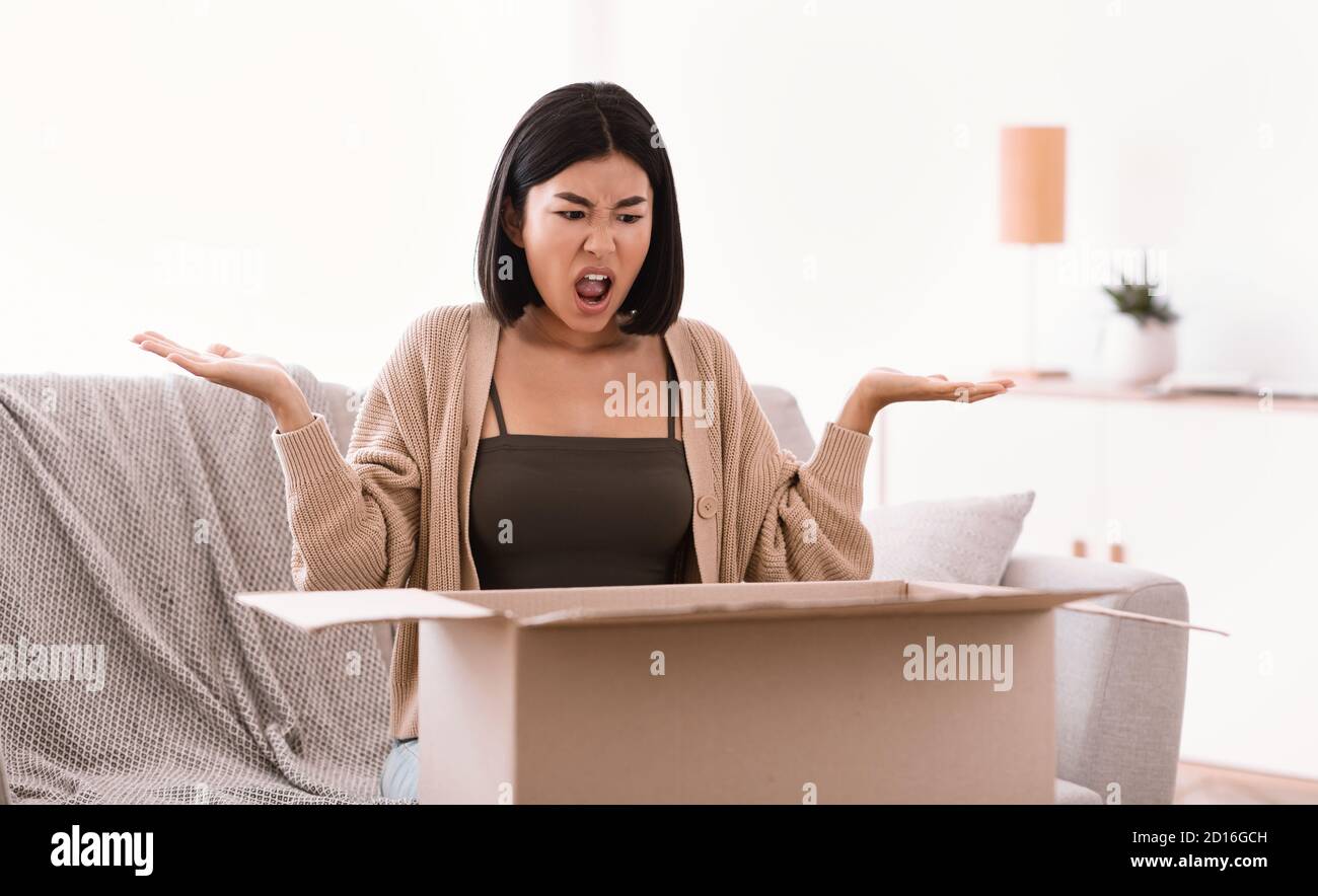 Angry young lady screaming after unpacking wrong parcel Stock Photo - Alamy