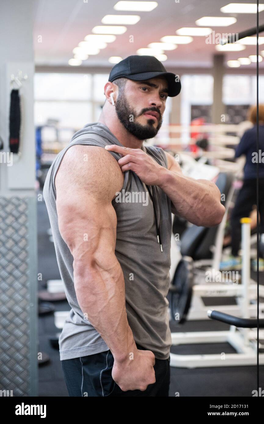 strong young bearded male showing big triceps muscle during posing in ...