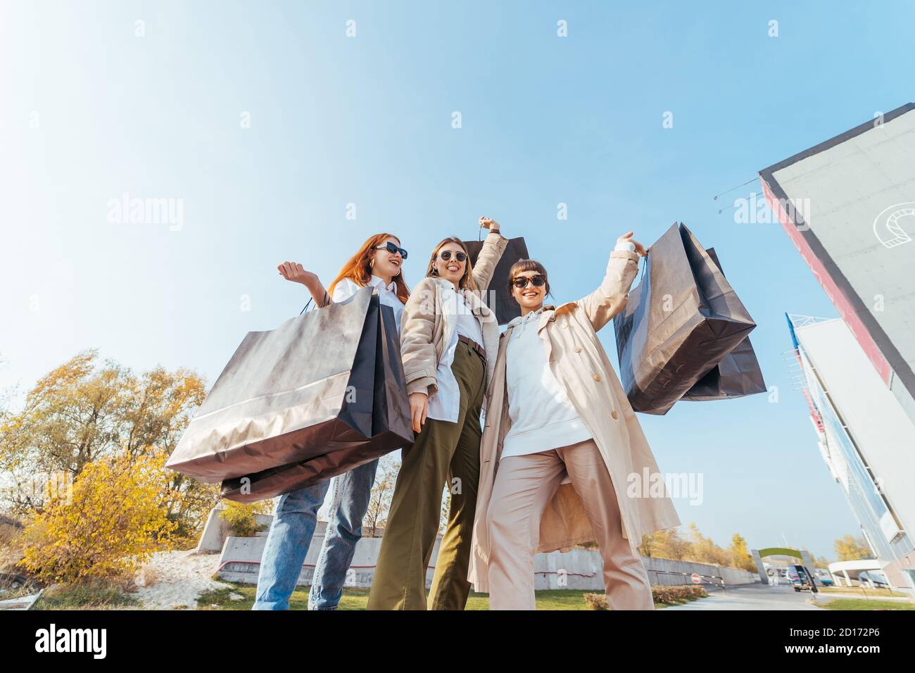 Young women with bags in hands posing for the camera Stock Photo - Alamy