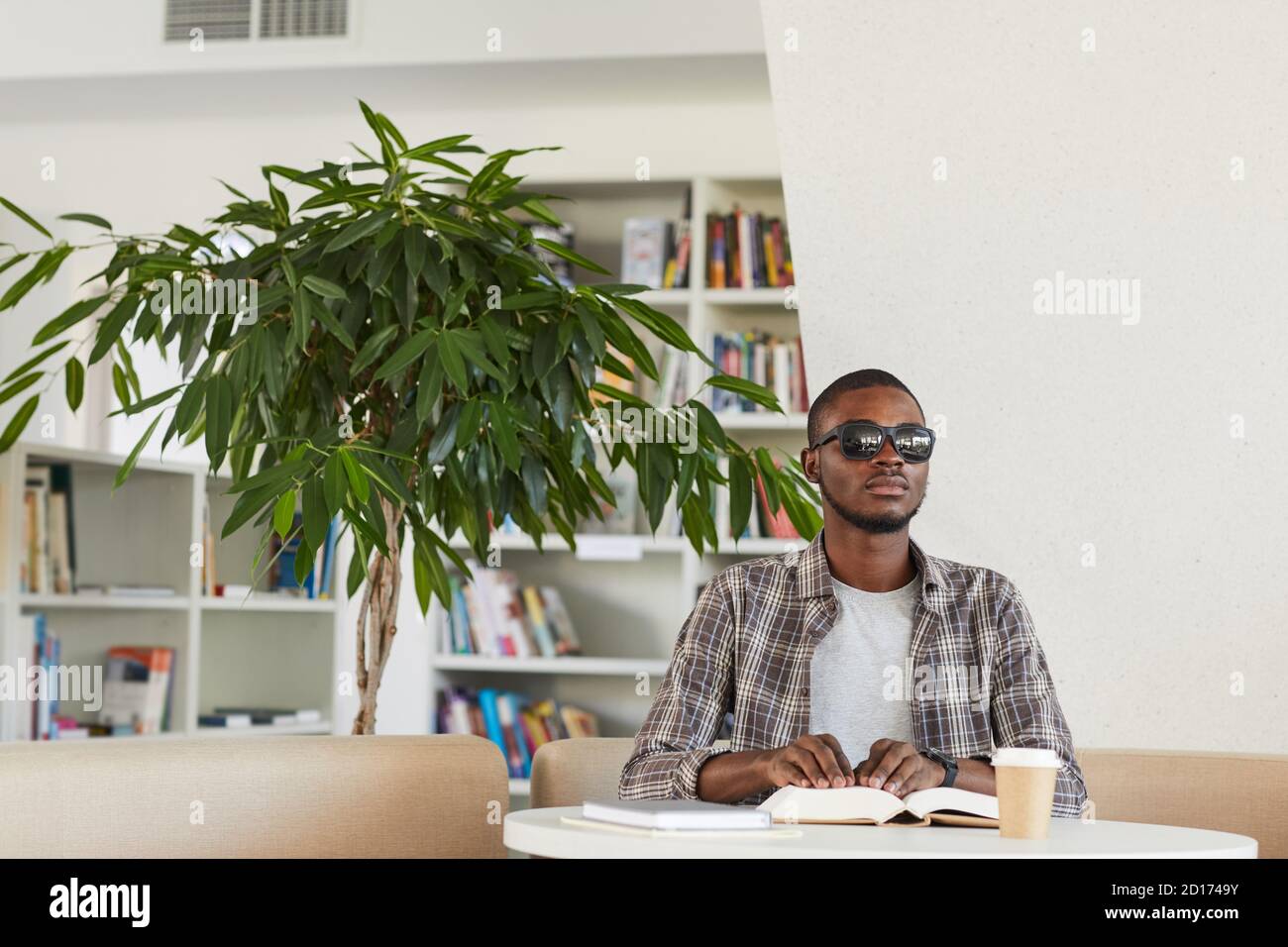 Front view portrait of blind African-American man reading Braille book ...