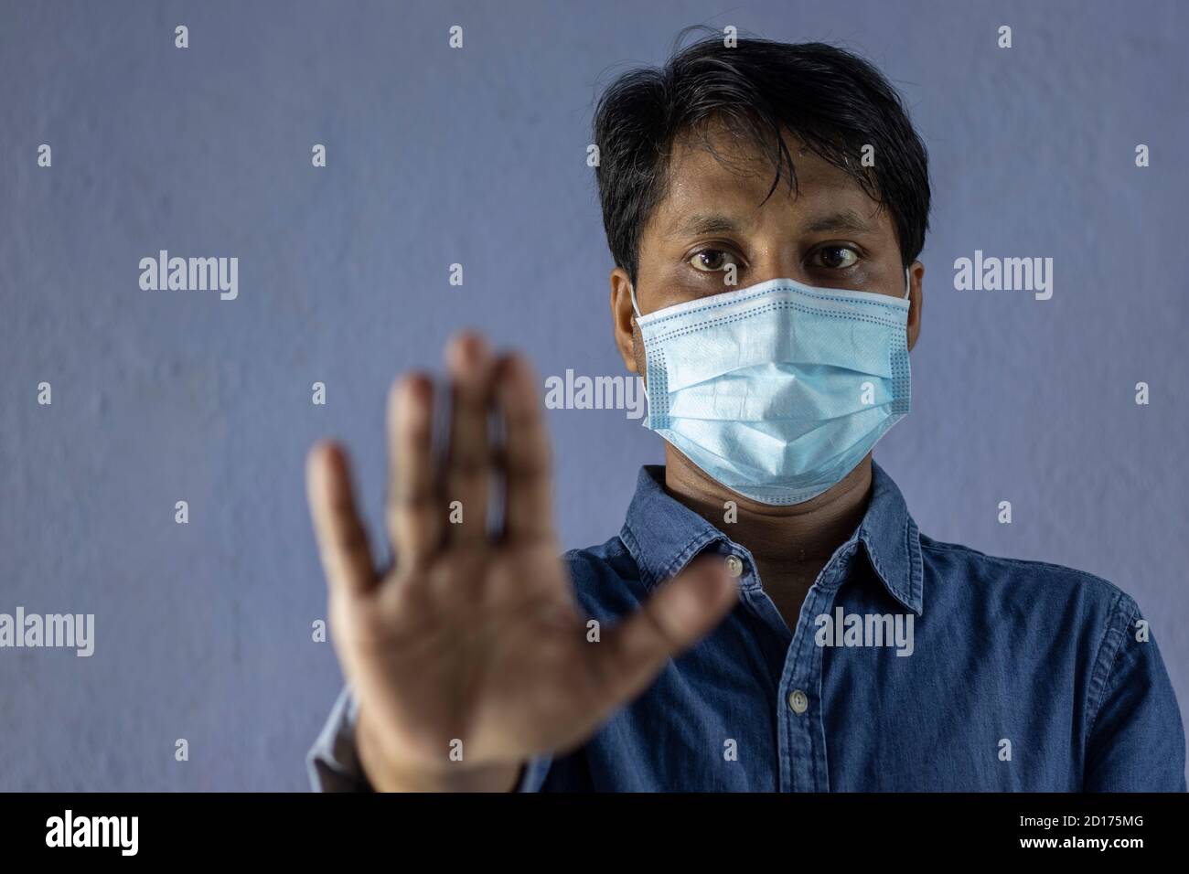 Serious Indian man showing open palm or stop gesture and looking at ...