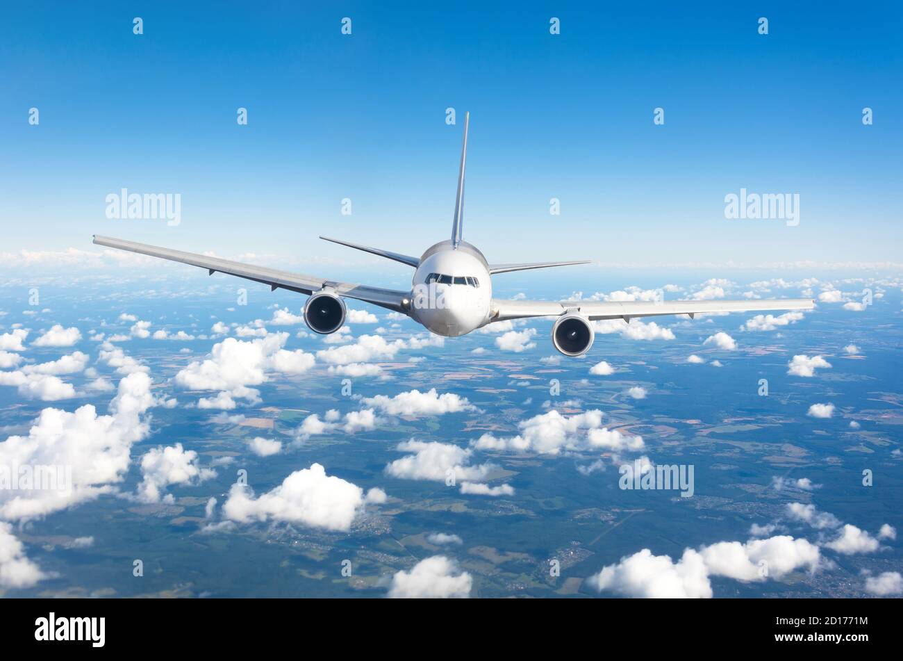 Passenger airplane flying at flight level high in the sky above cumulus ...