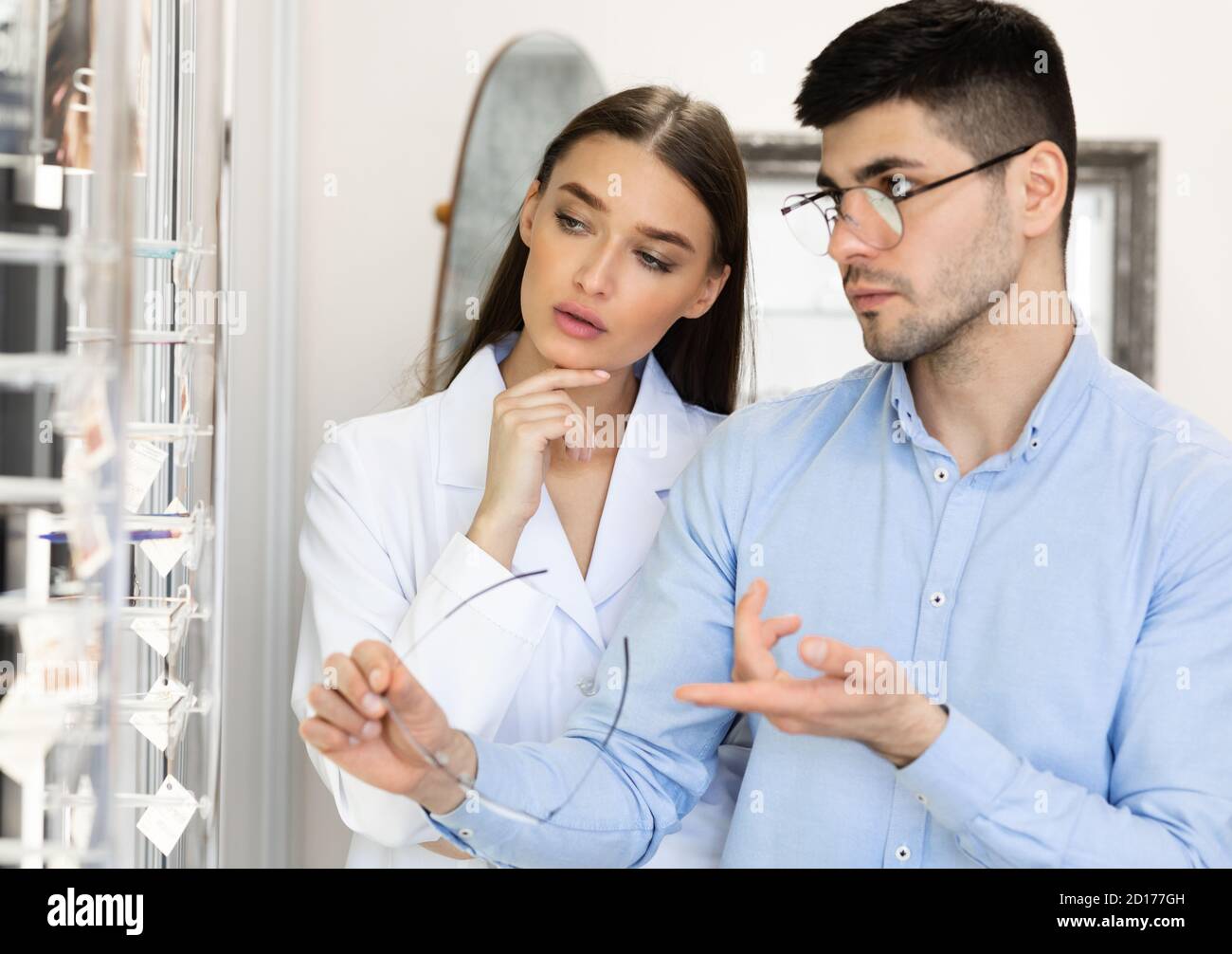 Optometrist helping client to choose new correction glasses Stock Photo ...
