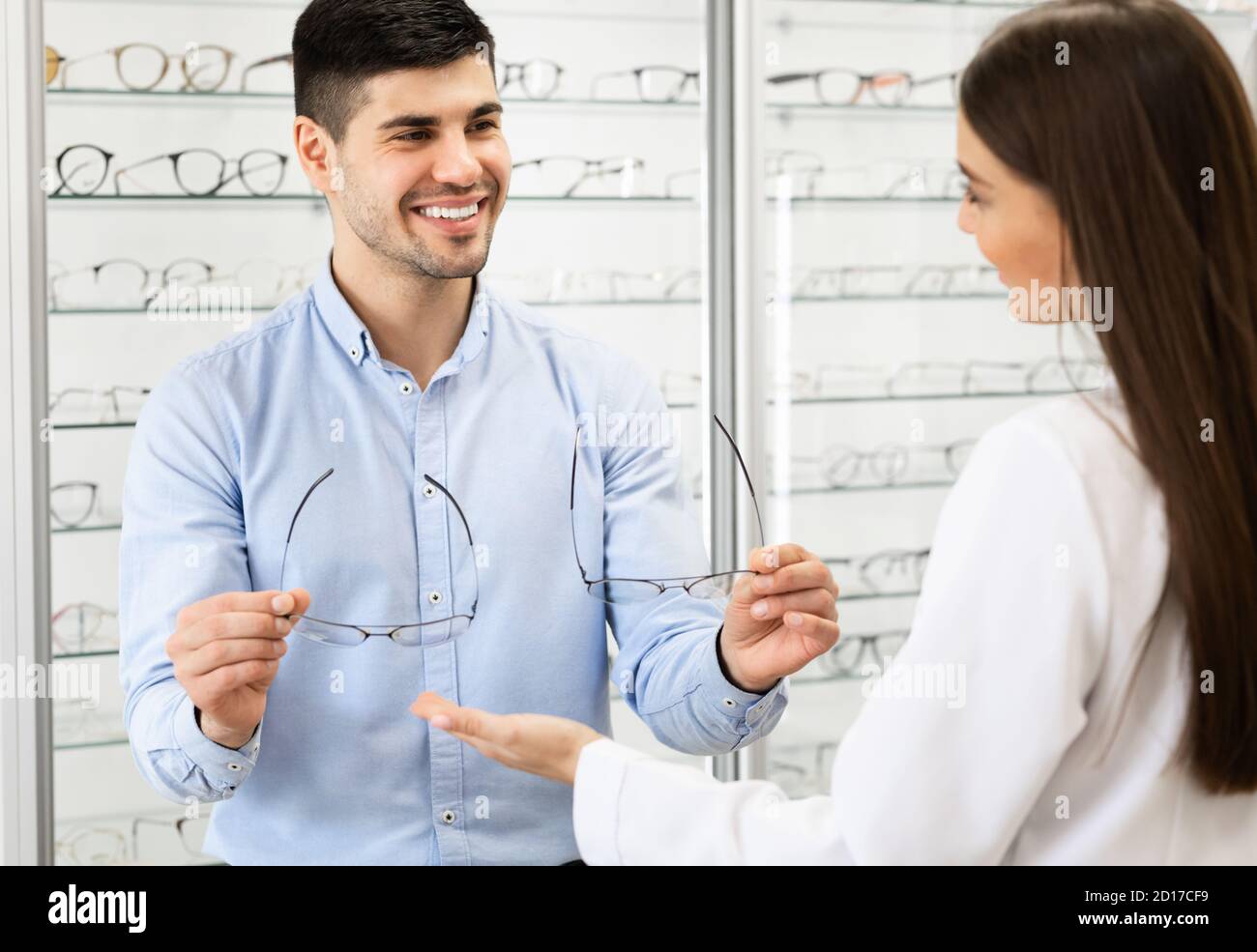 Optometrist helping man to choose new correction glasses Stock Photo ...