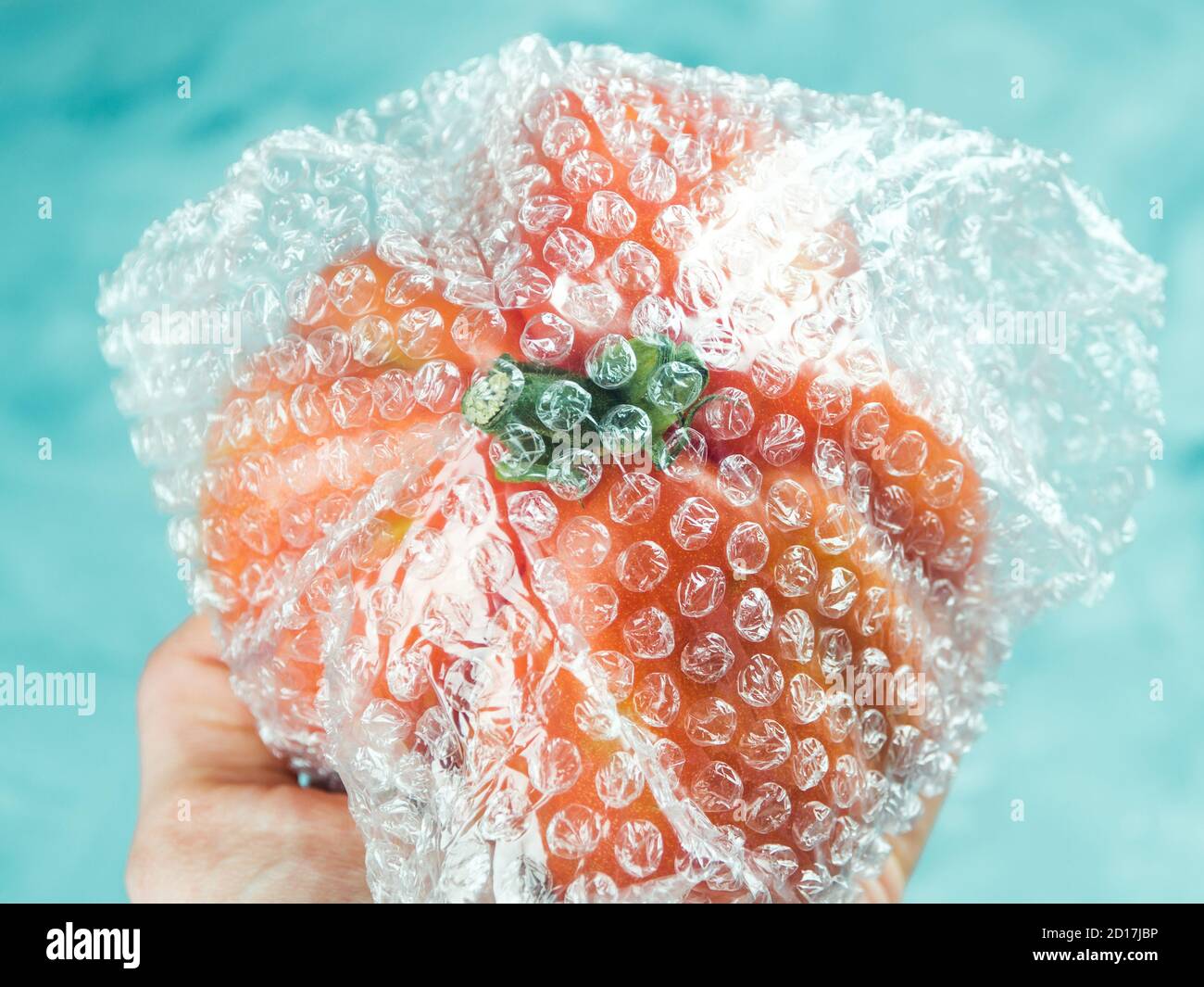 Tomato in plastic package on turquoise Stock Photo - Alamy
