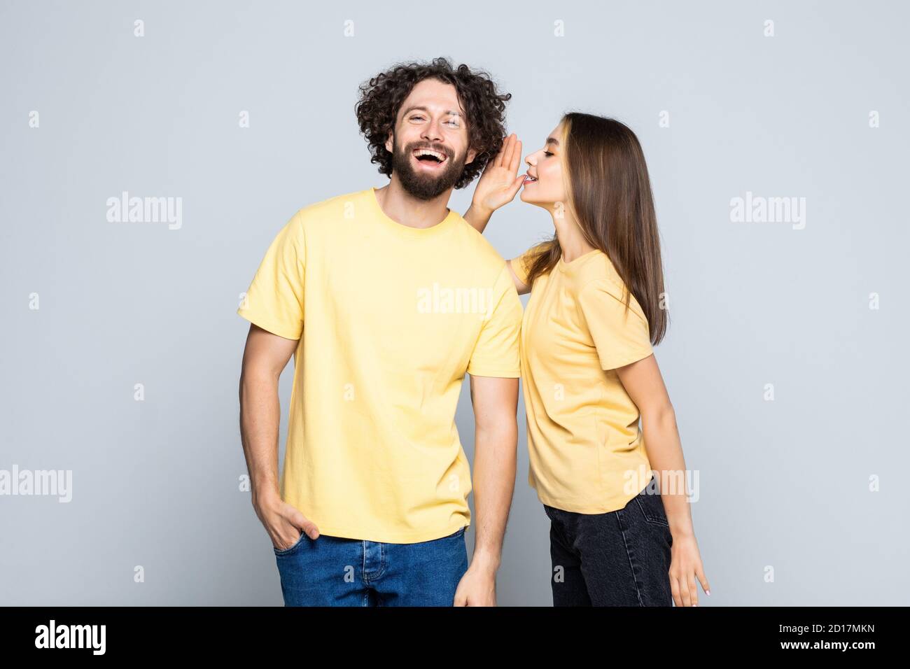 Excited asian couple standing isolated over gray background, telling ...