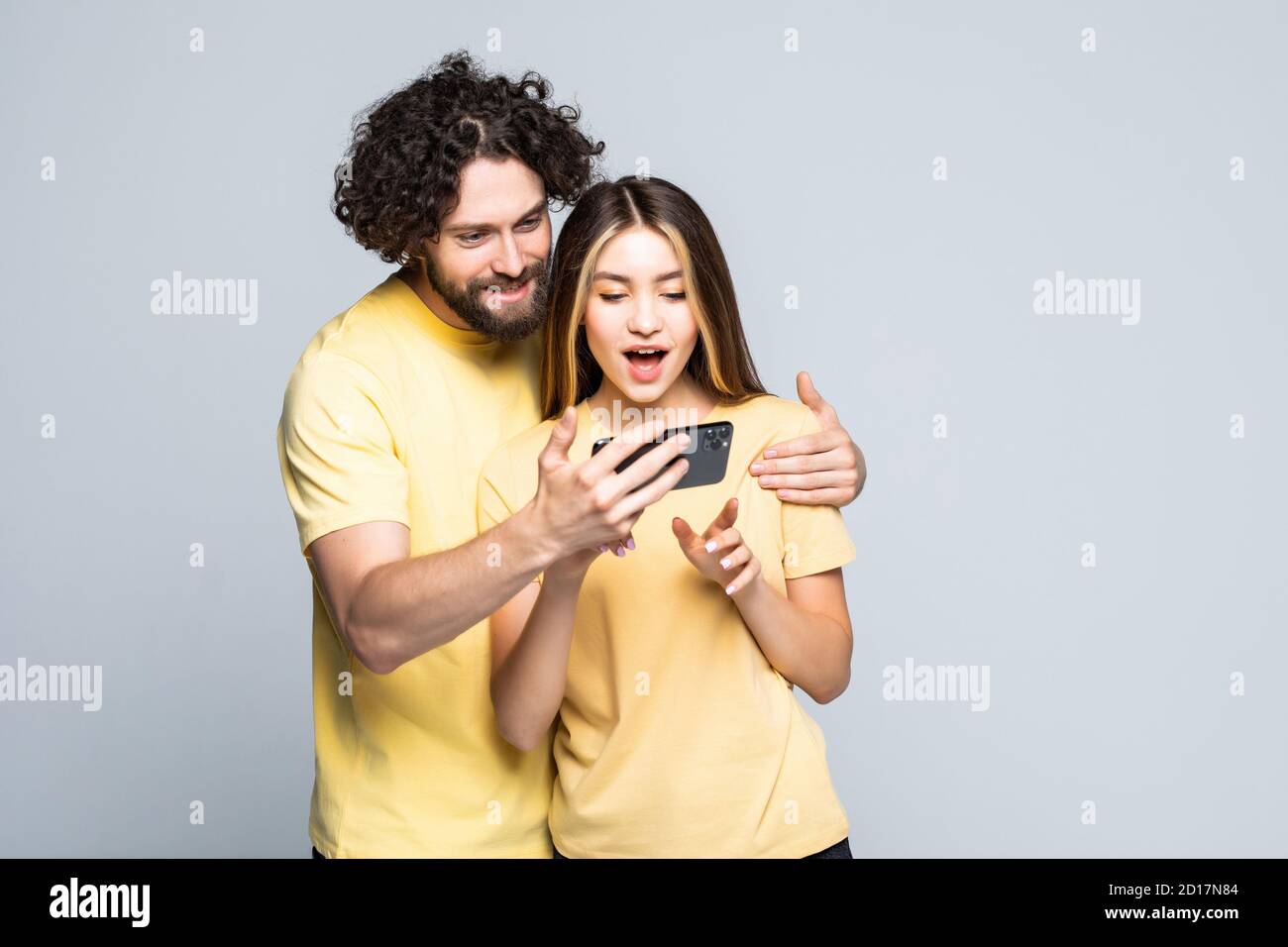 Happy friends laughing and watching a smart phone isolated on a white ...