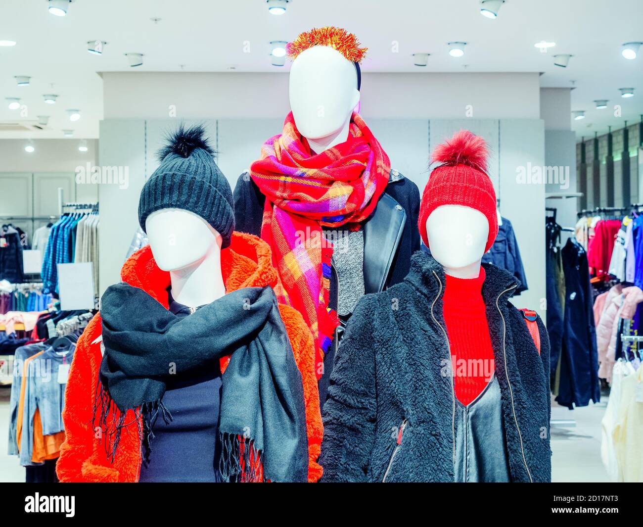 Three white mannequins without a face in winter clothes stand in a ...
