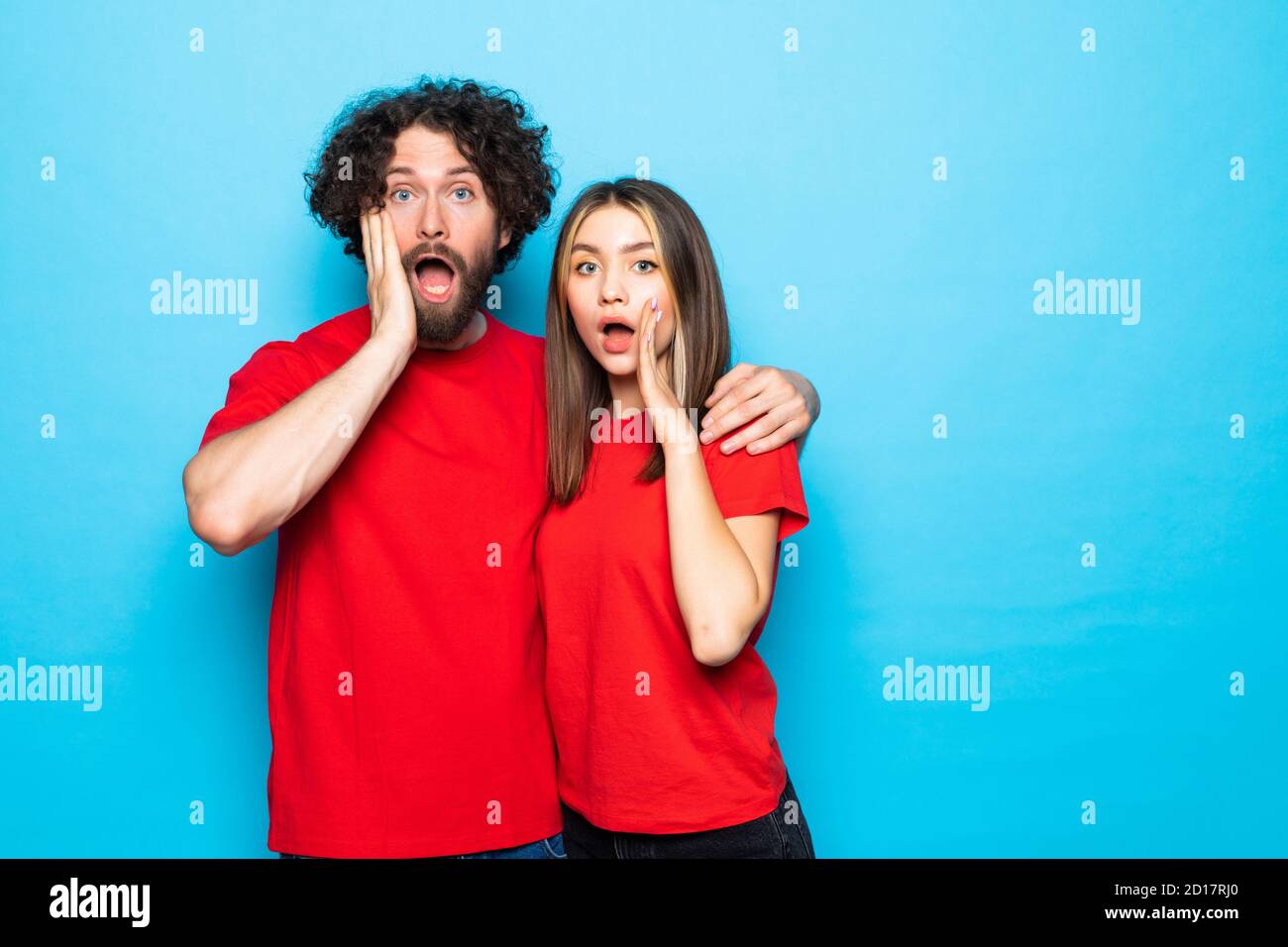 Shocked Couple Holding Hands Near Faces With Open Mouths While Looking