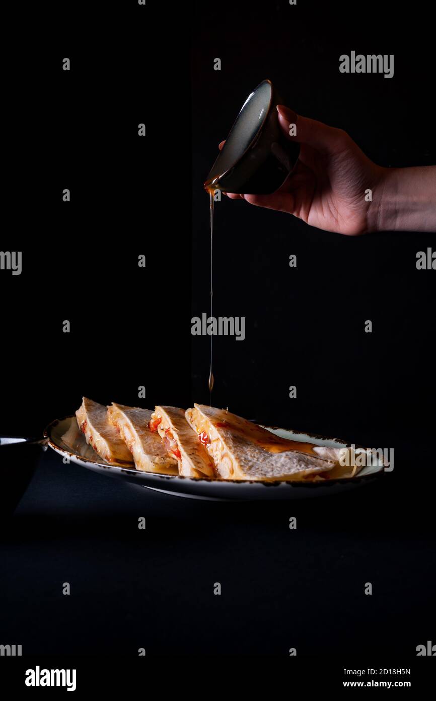 Vertical shot of a person pouring ketchup plate with quesadilla on a ...