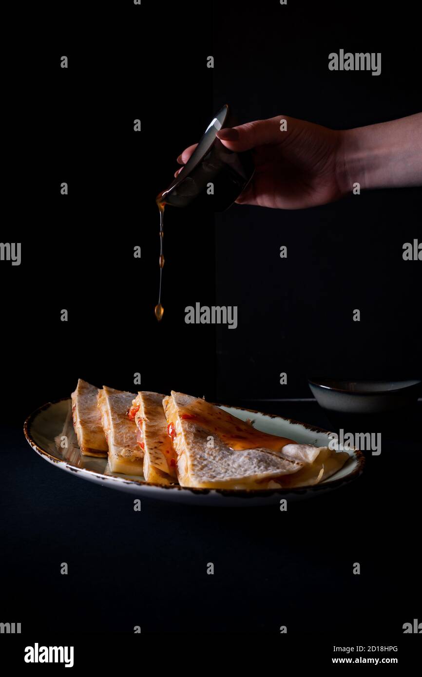 Vertical shot of a person pouring ketchup plate with quesadilla on a ...