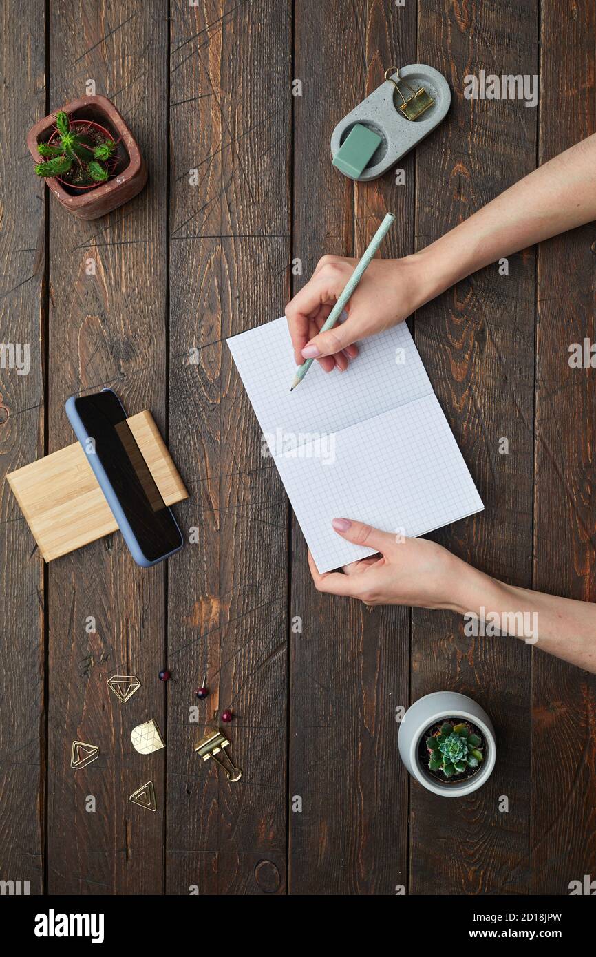 Minimal above view flat lay of female hands writing in planner over ...