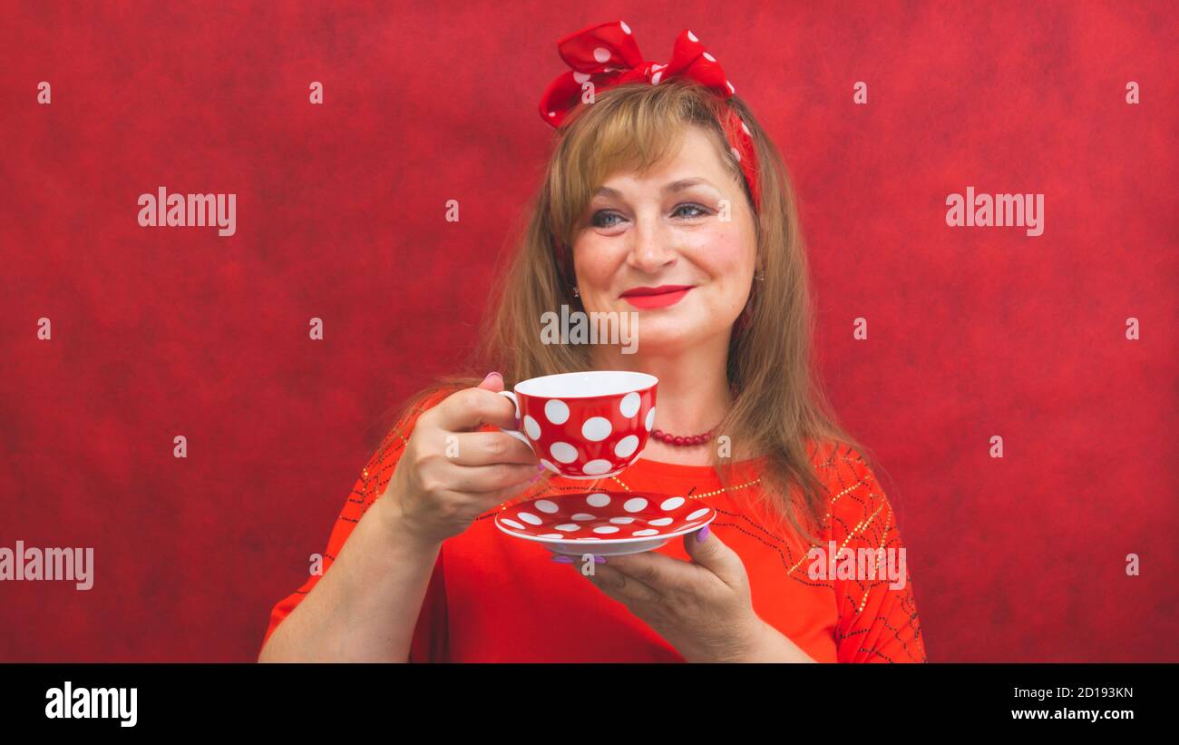 Woman in red posing on the red background. spotted cup with saucer in ...