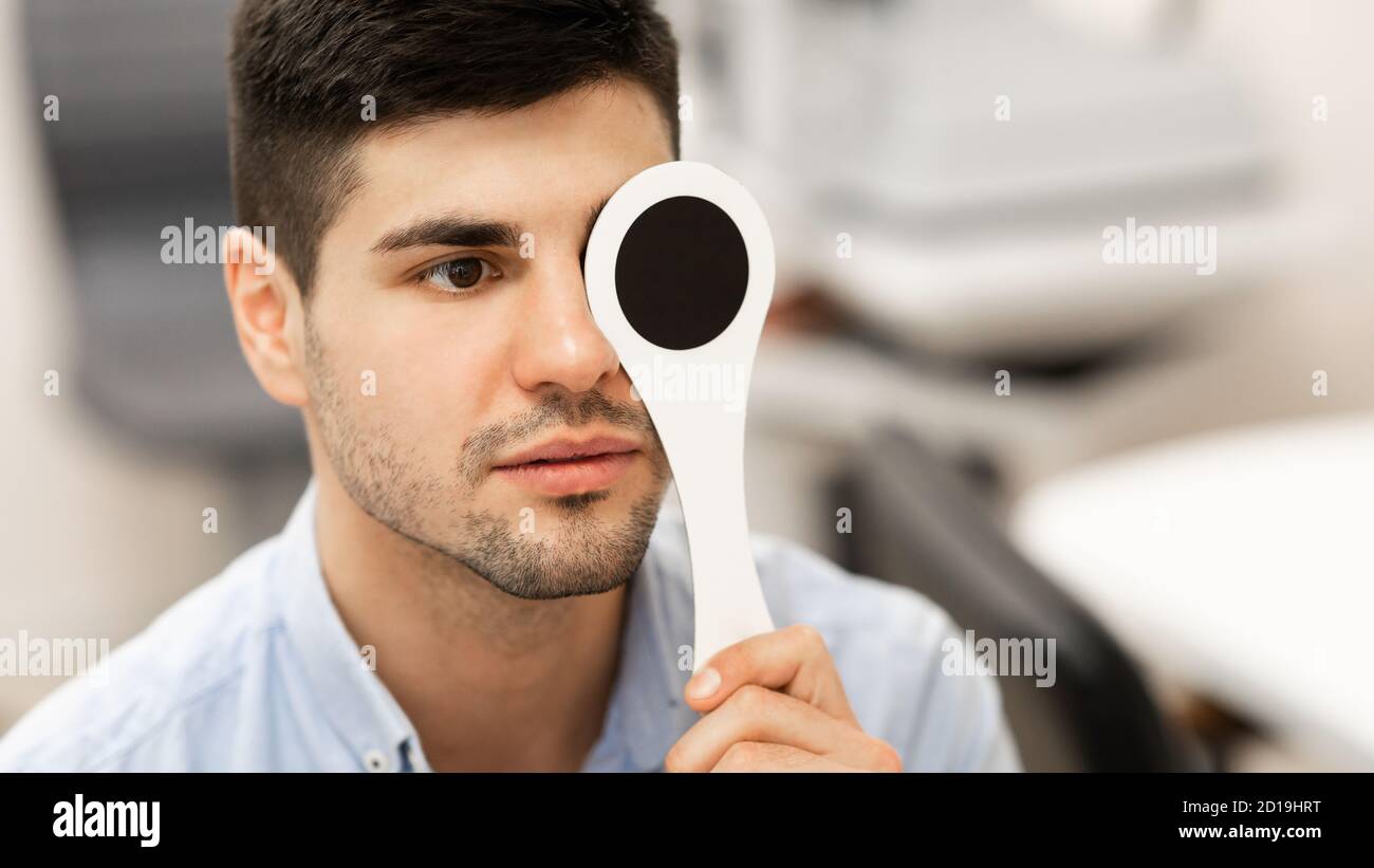 Serious male patient doing eye test in clinic Stock Photo - Alamy