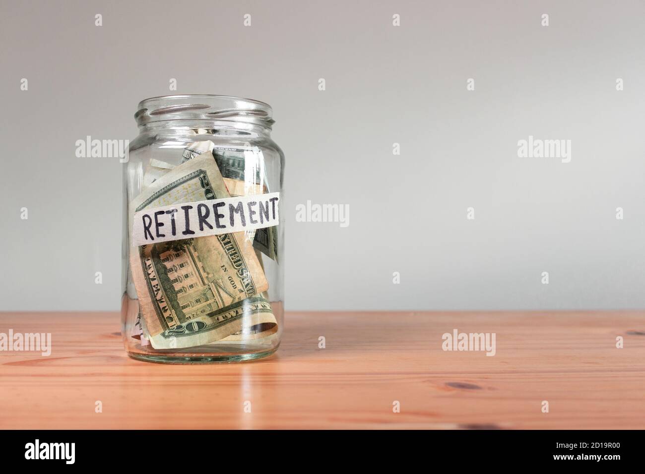 US Dollar bills in a glass jar labeled "retirement Stock Photo - Alamy