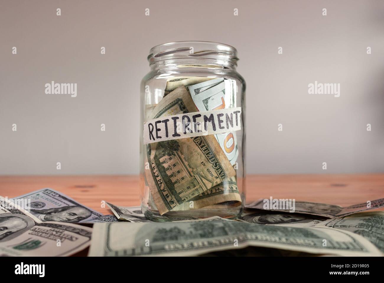 US Dollar bills in a glass jar labeled "retirement Stock Photo - Alamy