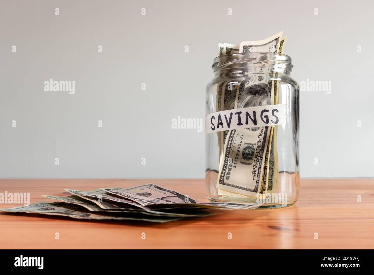 US Dollar bills in a glass jar labeled "savings Stock Photo - Alamy