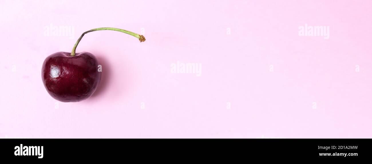 Cherry on pink plain background Stock Photo - Alamy