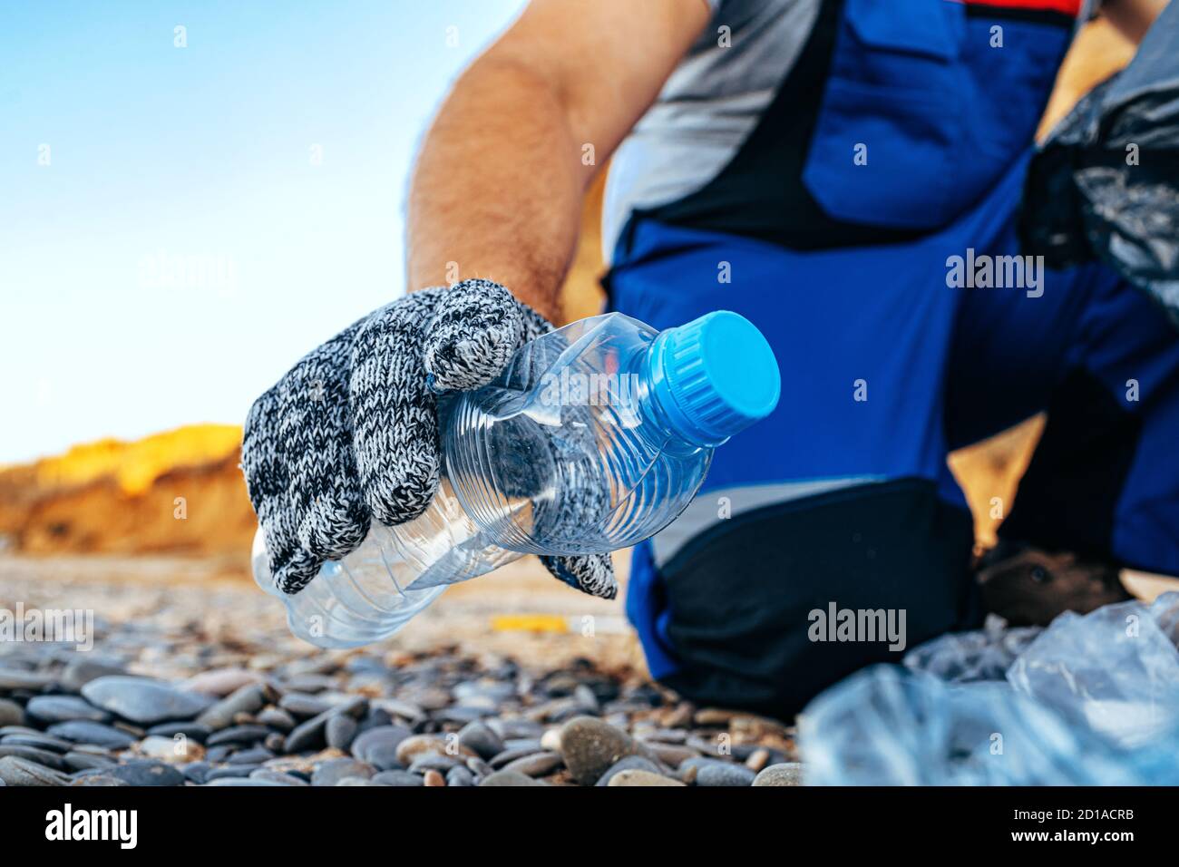 Hand of a man volunteer grabbing plastic litter into a waste bag ...