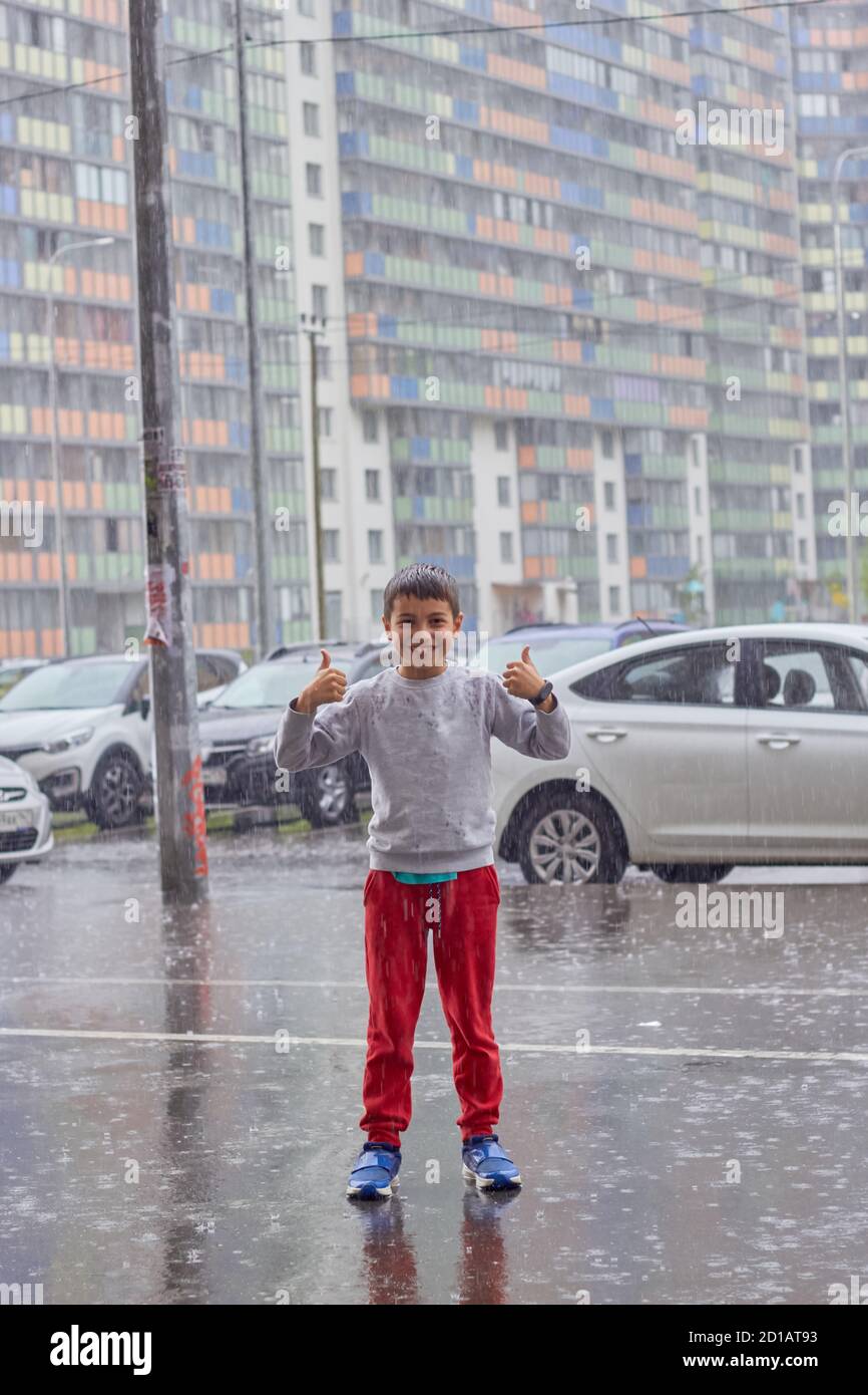 a child in the rain rejoices in a sudden heavy rain, city children ...
