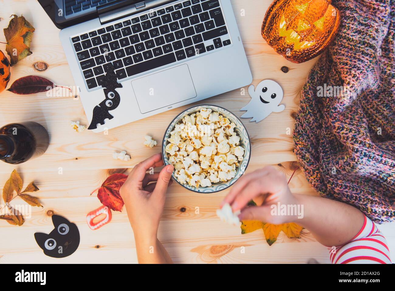 Top view Woman eating popcorn while watching Halloween movie. Laptop ...