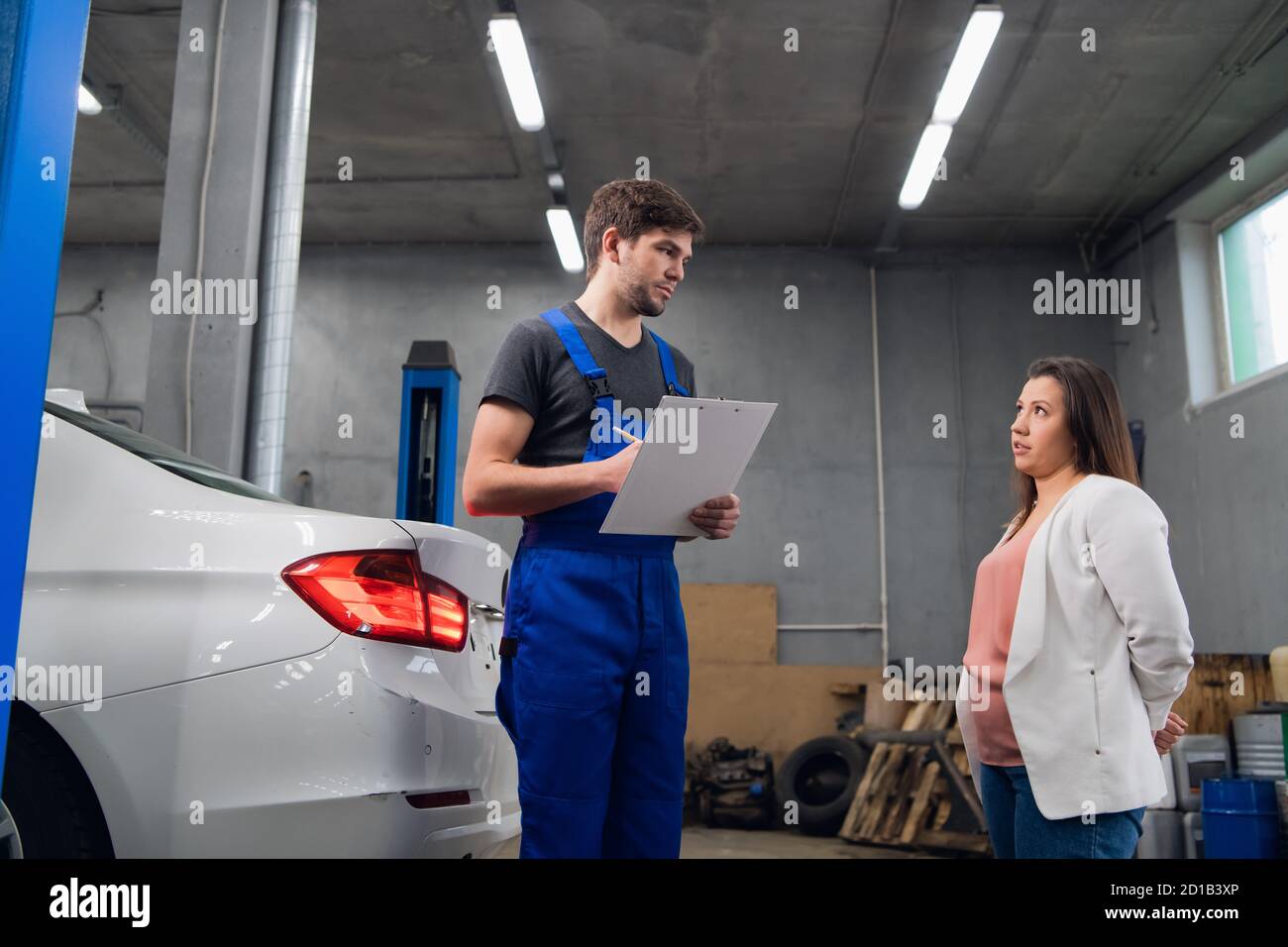 Repairman in a workshop talking with a client about a car repair Stock ...