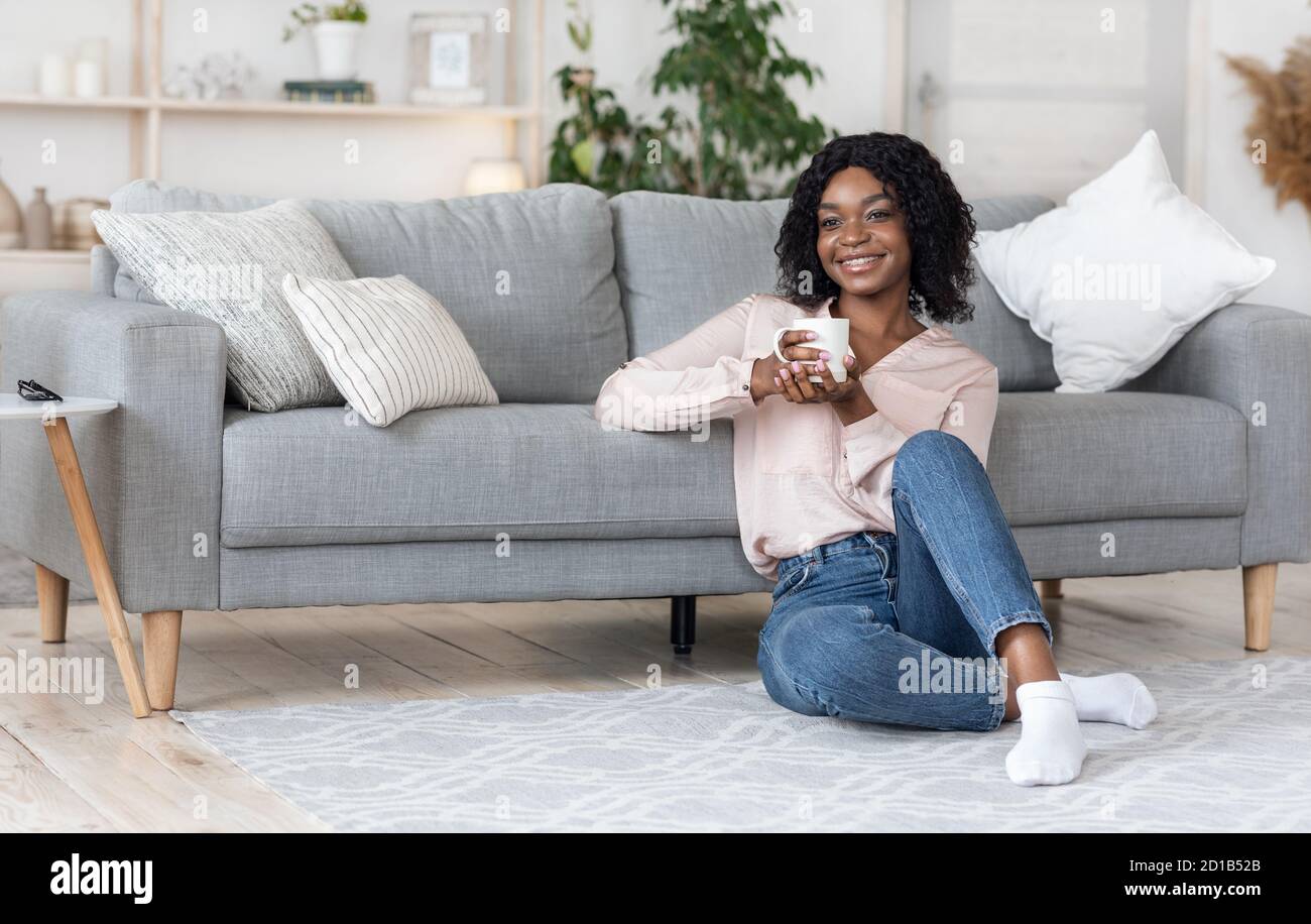 Dreamy African American Woman Unwinding At Home With Cup Of Coffee ...