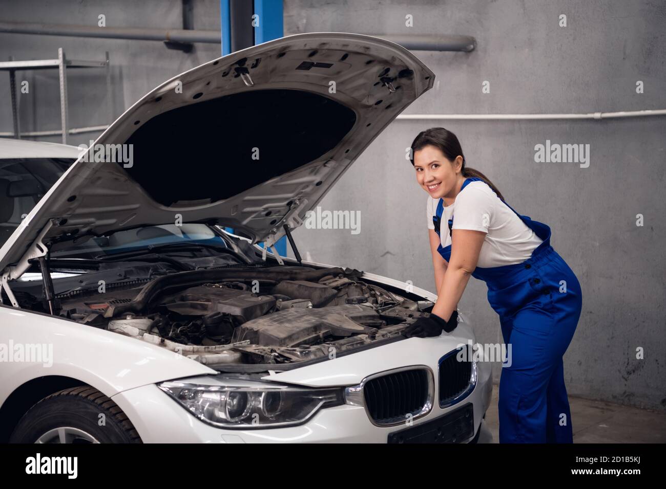 Female mechanic checks the engine of a white car Stock Photo - Alamy