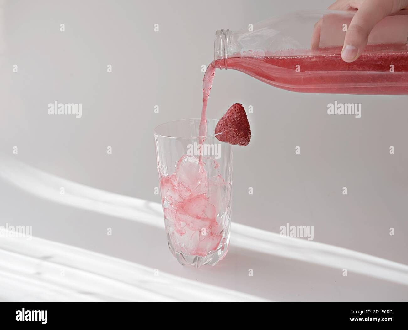 humans hand holding a bottle with strawberry juice. pouring juice into ...