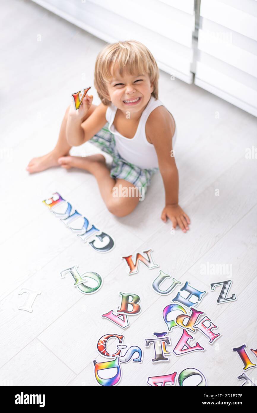Beautiful little boy learning letters on the floor at home Stock Photo ...