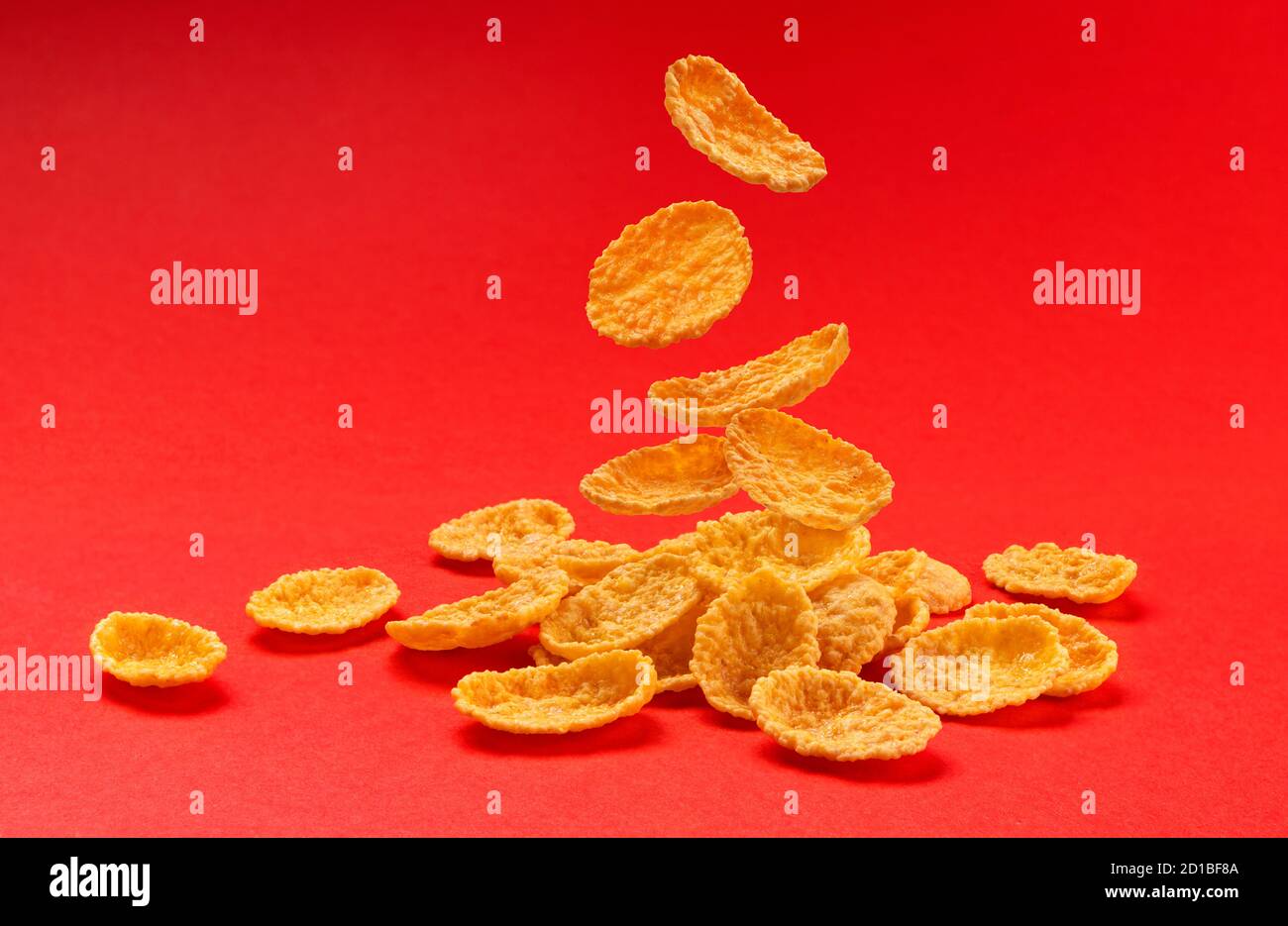 Falling corn flakes isolated on red color background, full depth of ...