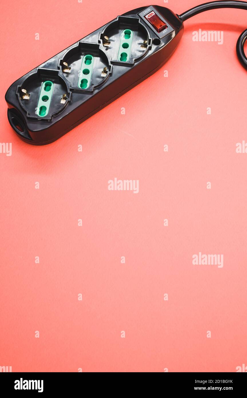 Black surge protector on a light red background Stock Photo - Alamy