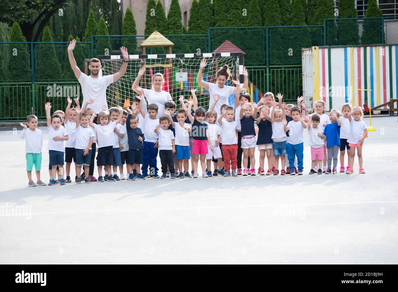 Group of children with coaches posing and waving before the lesson ...