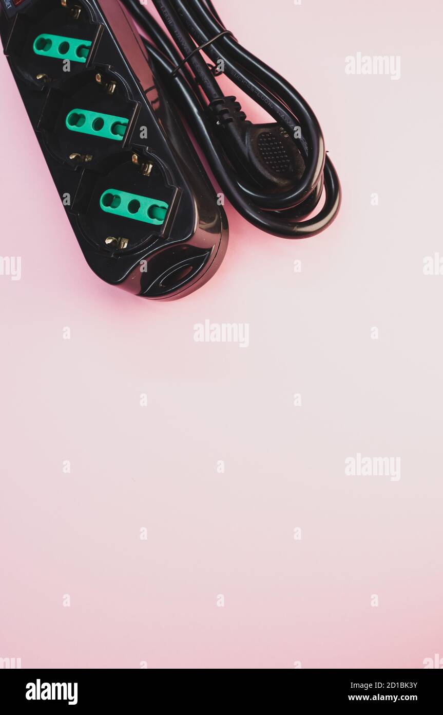 Black surge protector on a light pink background Stock Photo - Alamy