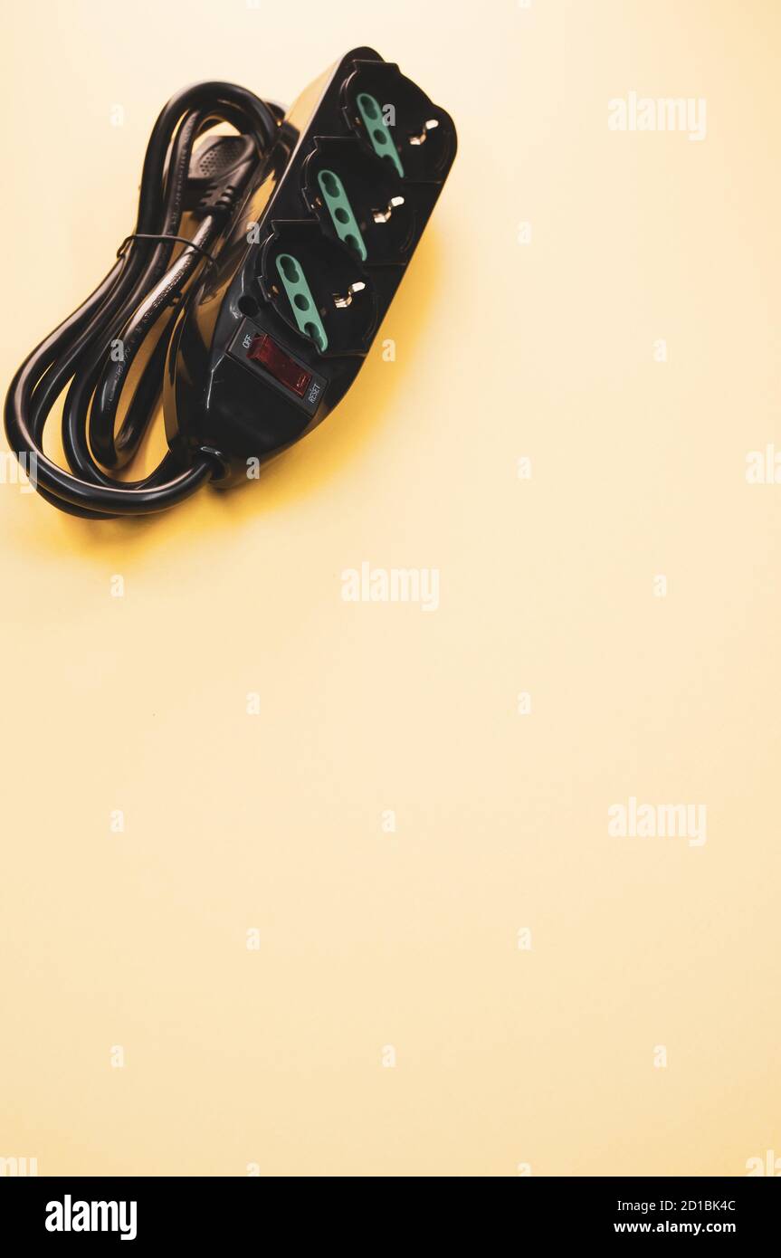 Black surge protector on a yellow background Stock Photo - Alamy