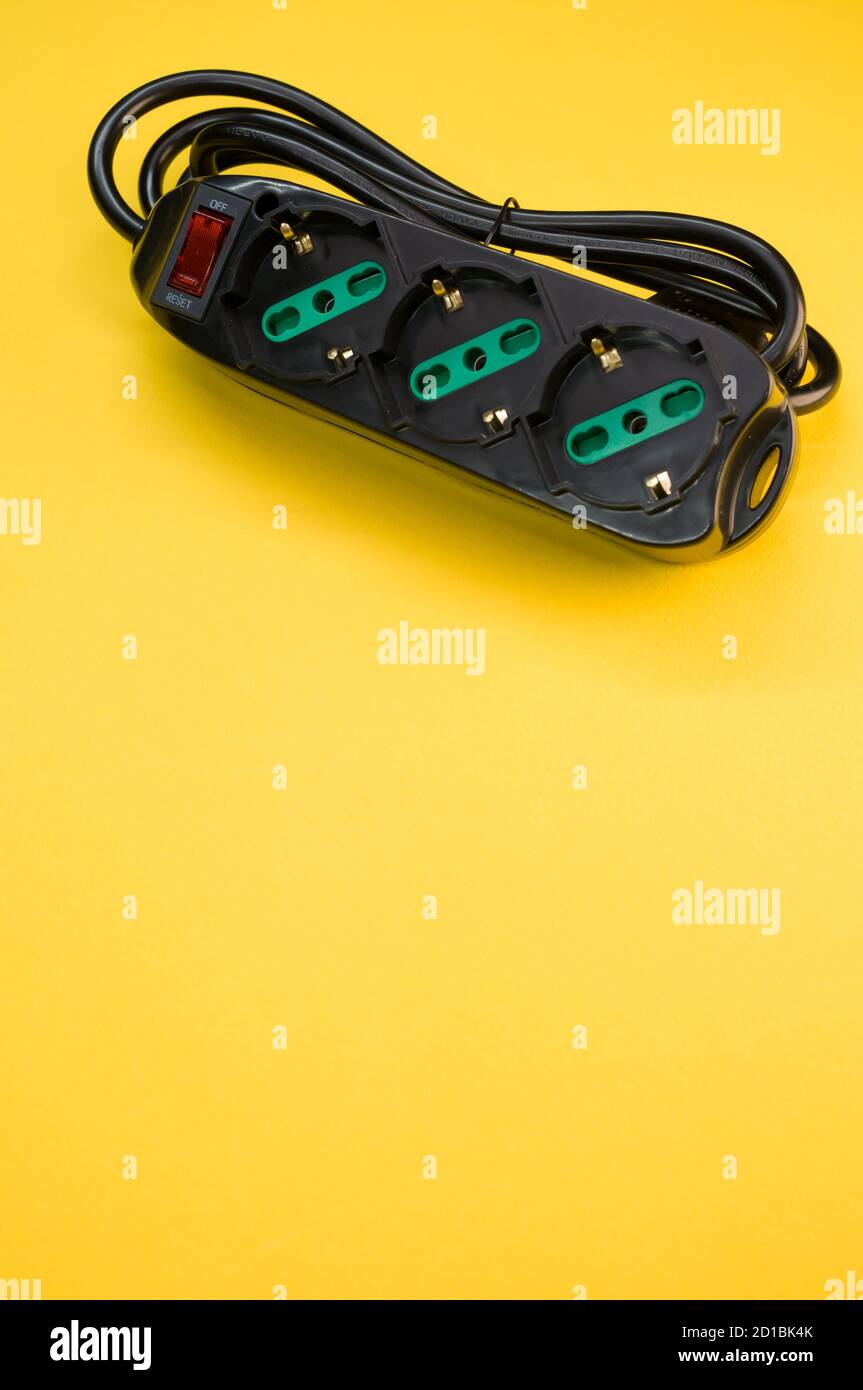 Black surge protector on a yellow background Stock Photo - Alamy