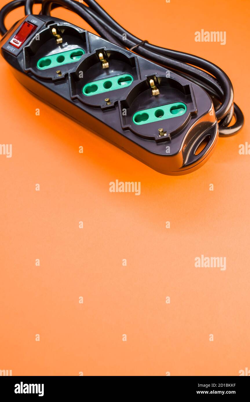 Black surge protector on an orange background Stock Photo - Alamy